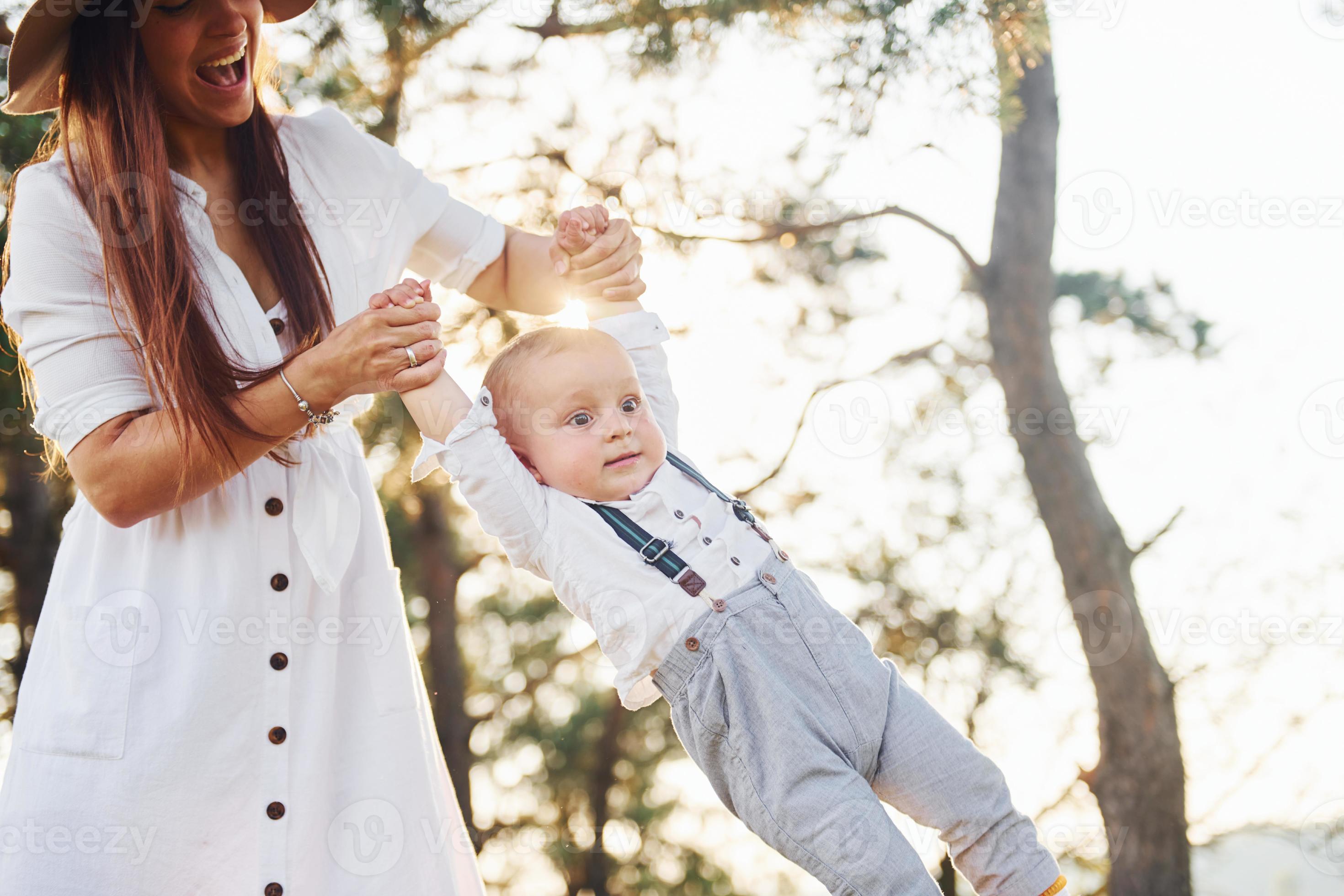 Young mother with her little son is outdoors in the forest. Beautiful ...