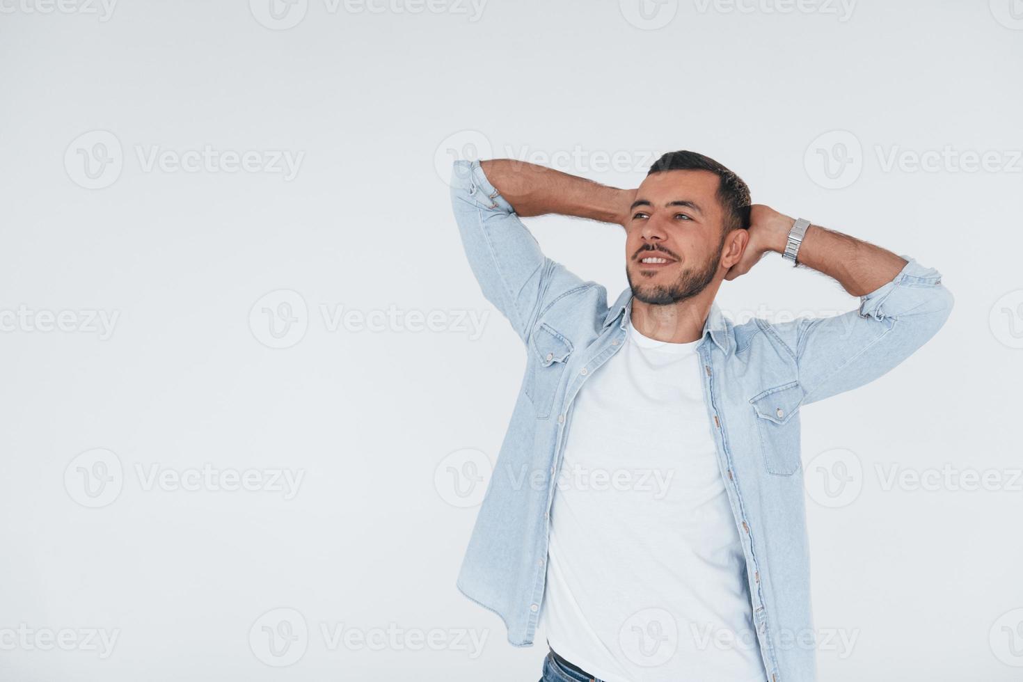 Feels relaxed. Young handsome man standing indoors against white ... Feels relaxed. Young handsome man standing indoors against white ...