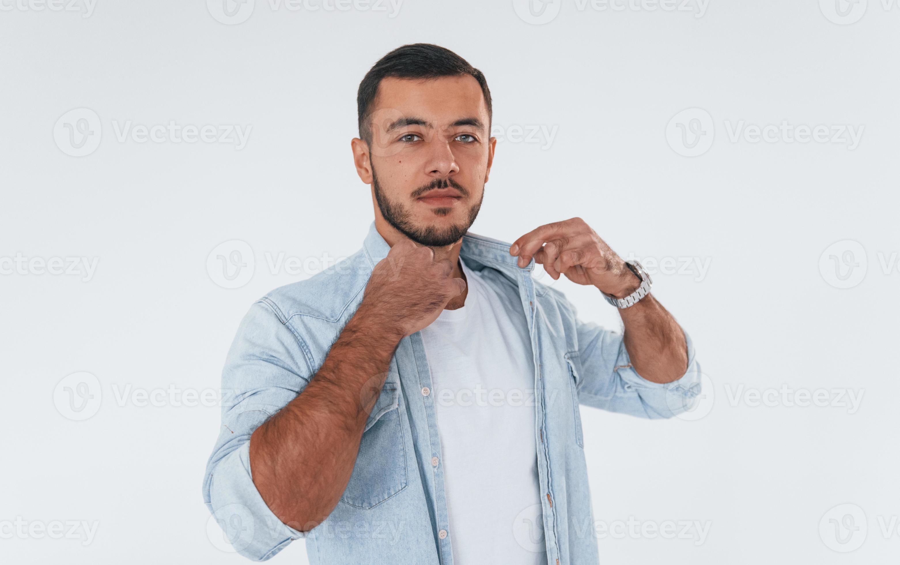 Fashionable young man standing indoors against white background ...