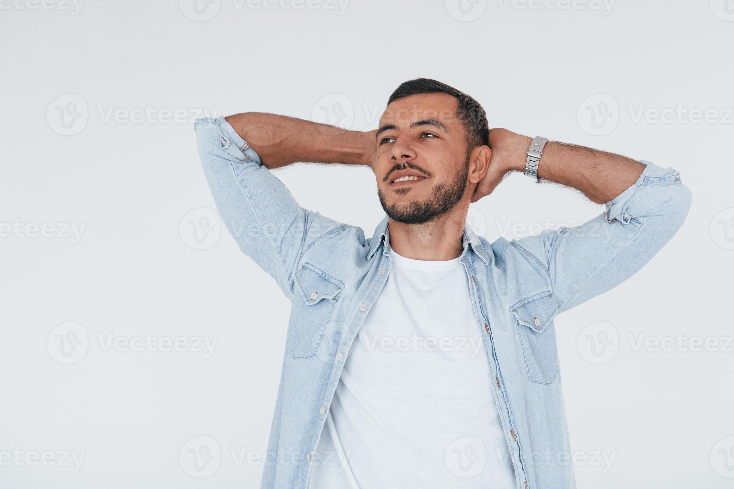 Feels relaxed. Young handsome man standing indoors against white ... Feels relaxed. Young handsome man standing indoors against white ...