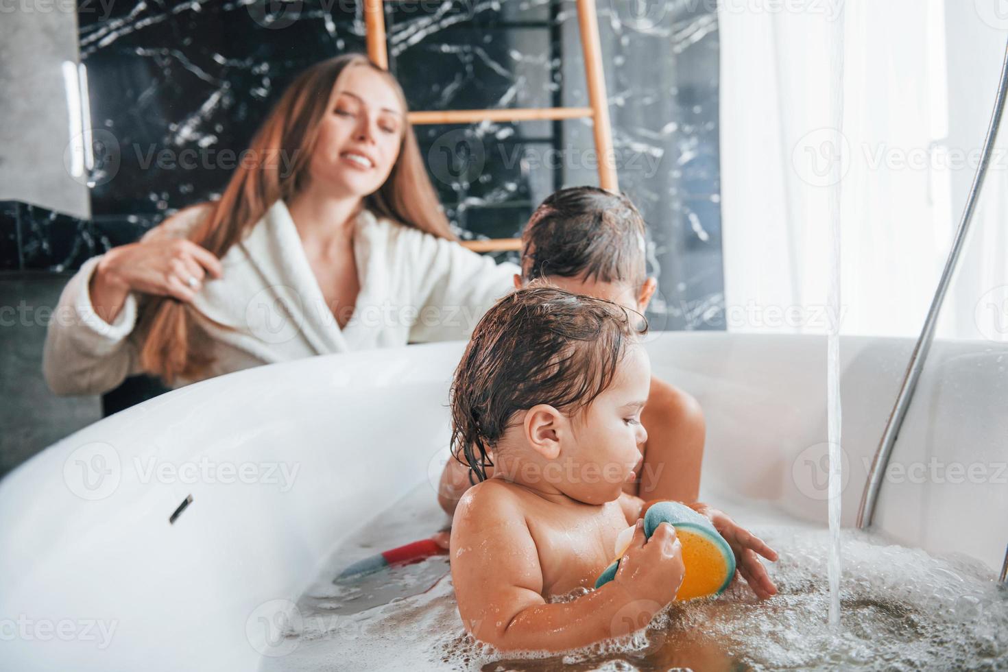 Having fun. Young mother helps her son and daughter. Two kids washing in the bath 15362988 Stock ...