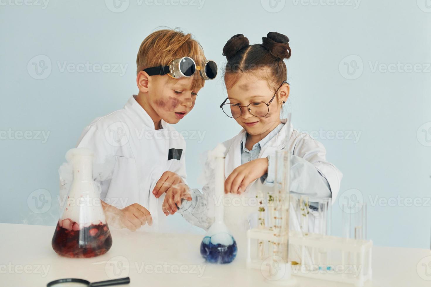 chica con chico trabajando juntos. los niños con batas blancas juegan a ...