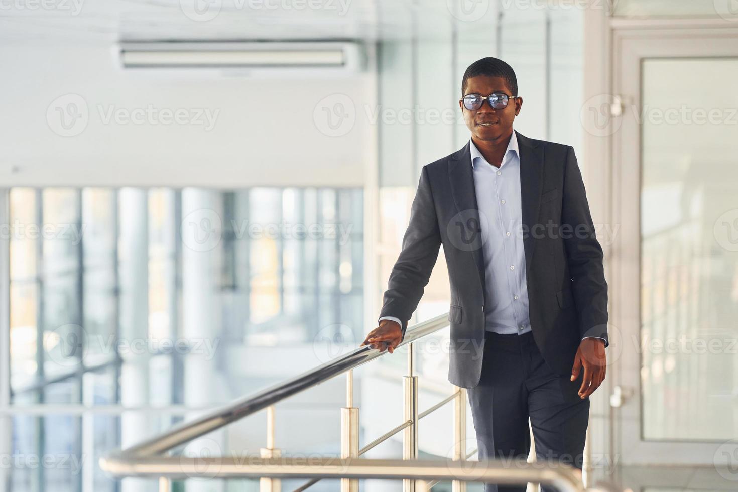 Leaning on the railings. Young african american businessman in black ...
