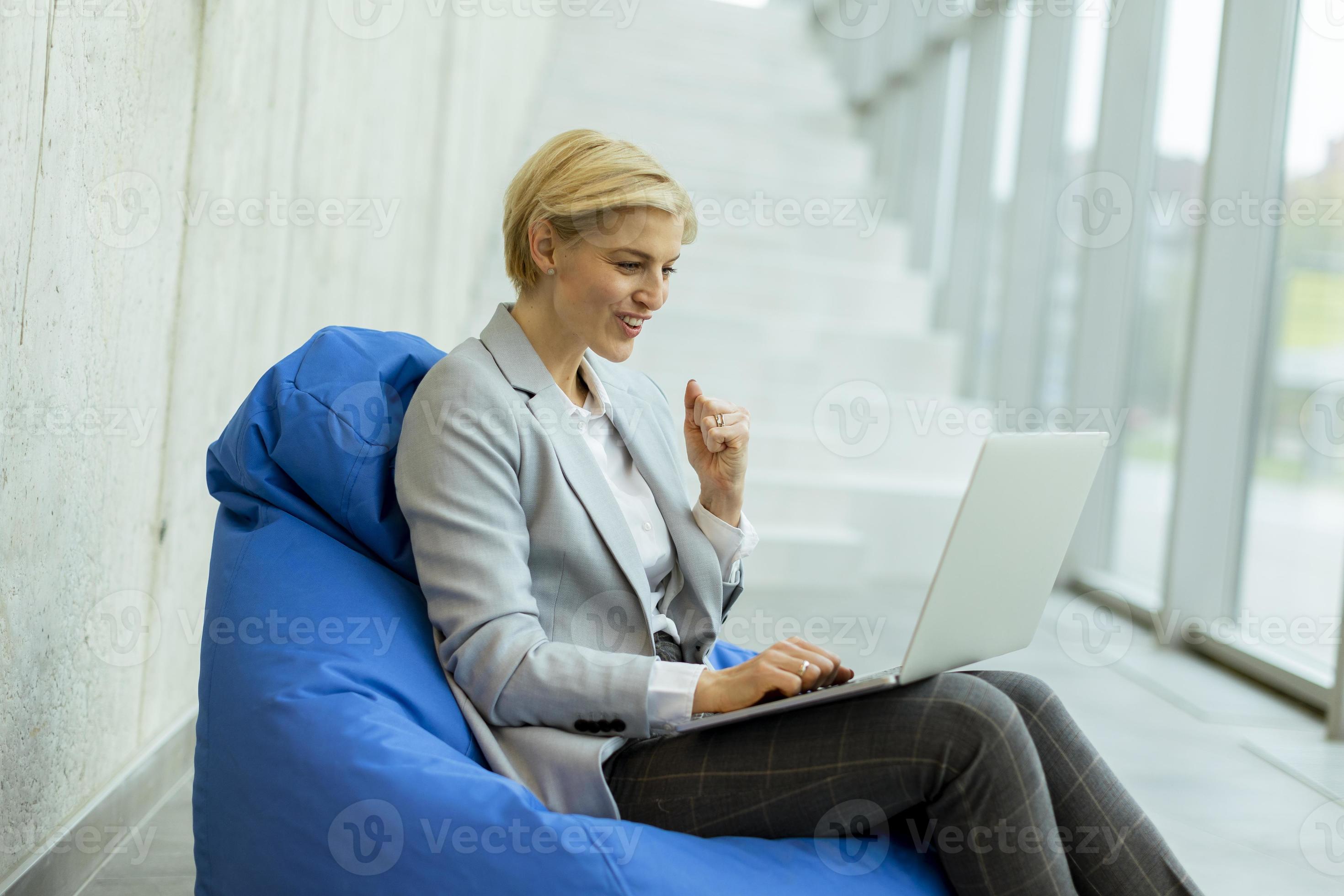Businesswoman using laptop computer on lazy bag in the modern office ...