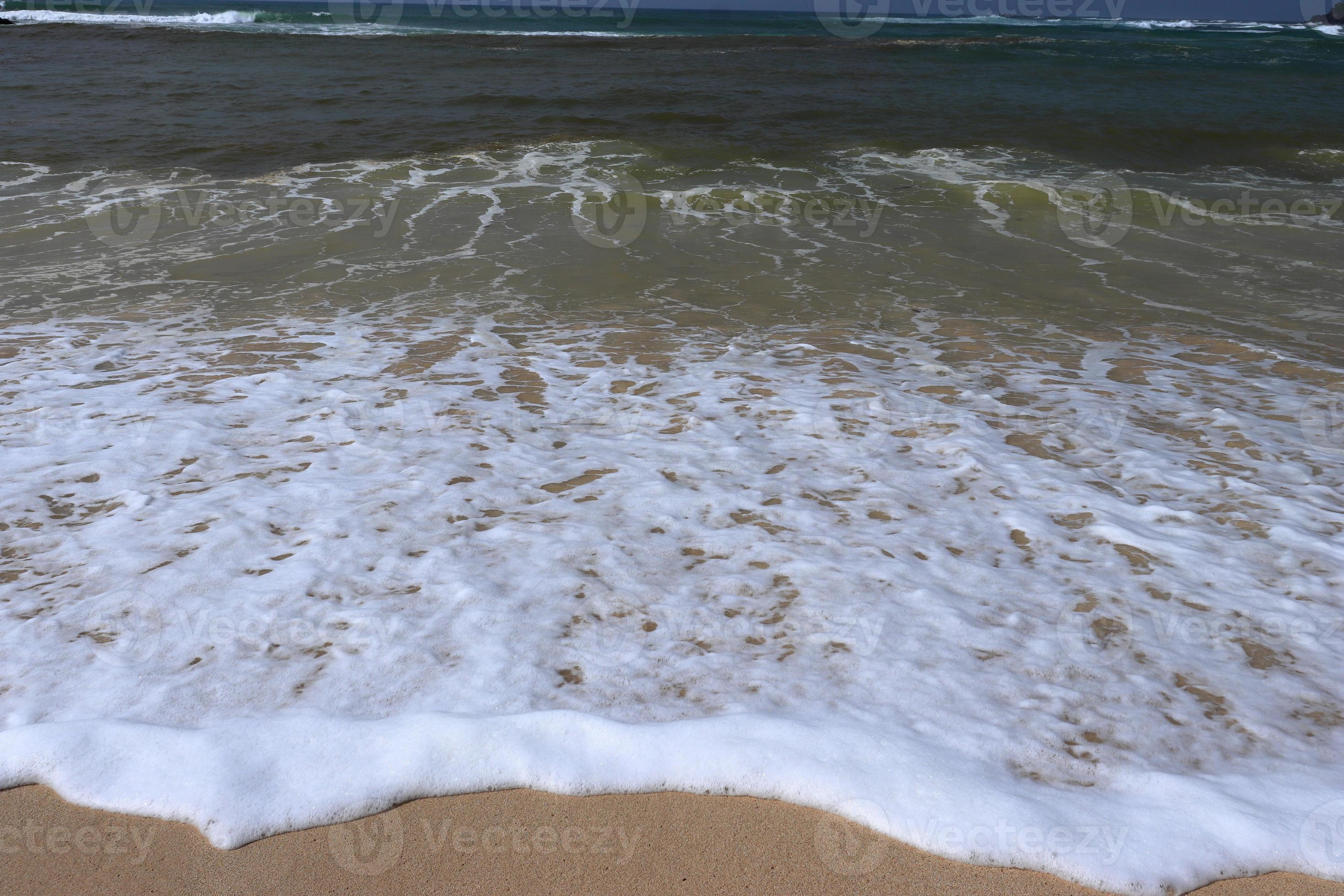 Ocean shore with sandy beach and advancing wave. Water foam with smooth ...