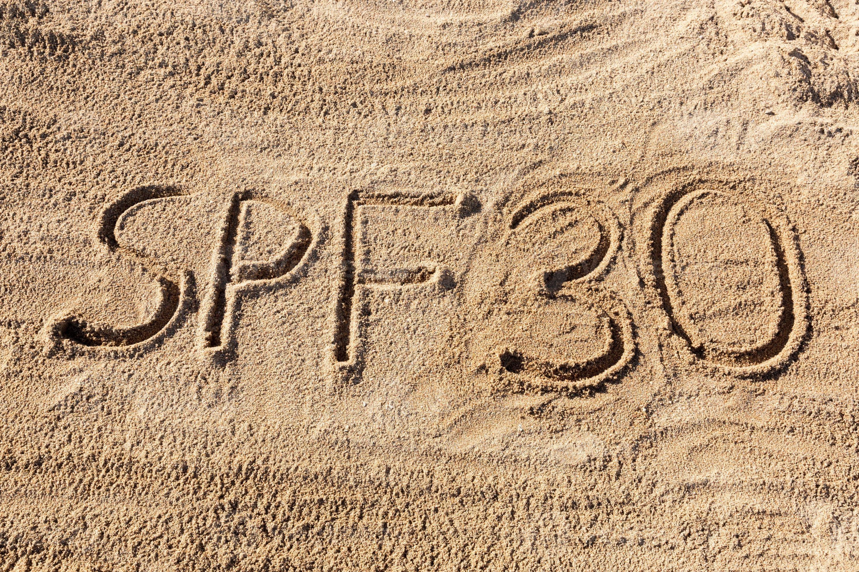 Sun protect factor thirty concept. SPF 30 word written on the beach ...