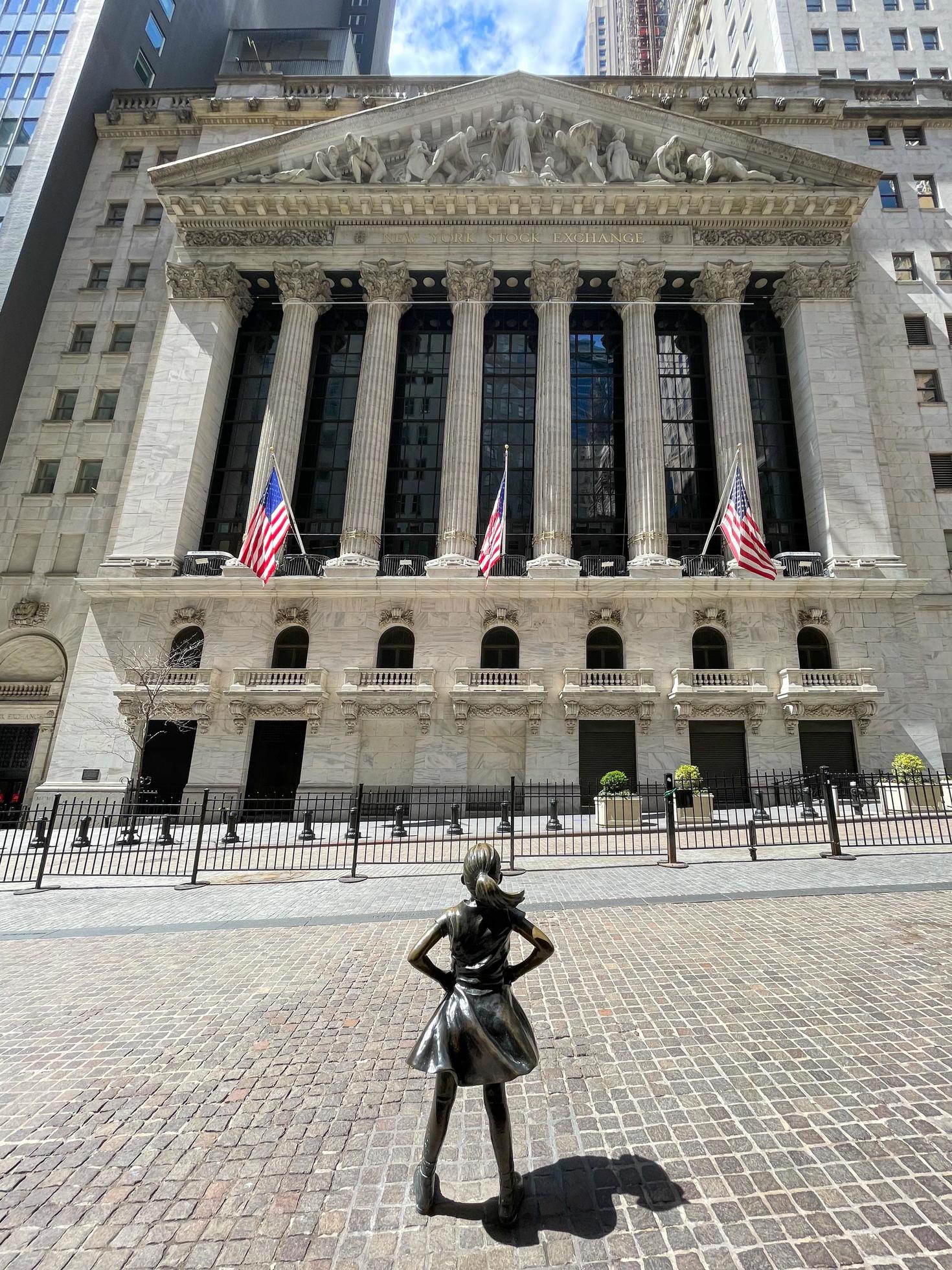 New York City - April 18, 2021 - Fearless Girl Statue looking up at New York Stock Exchange ...