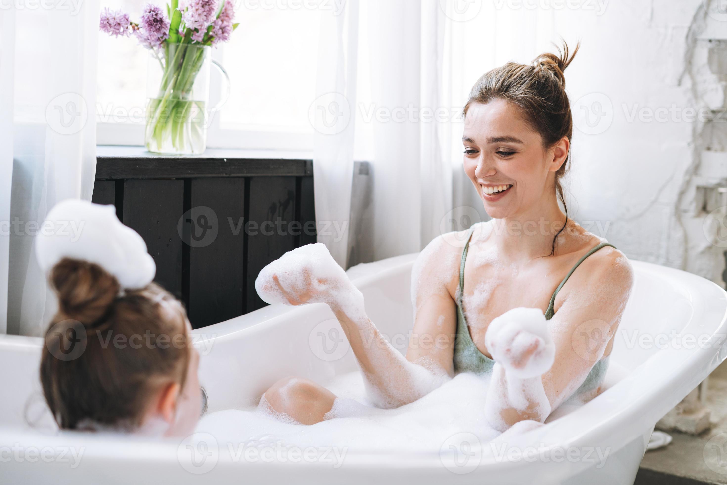 Young mother woman and little tween girl daughter having fun in bath with foam at home 16276966 ...
