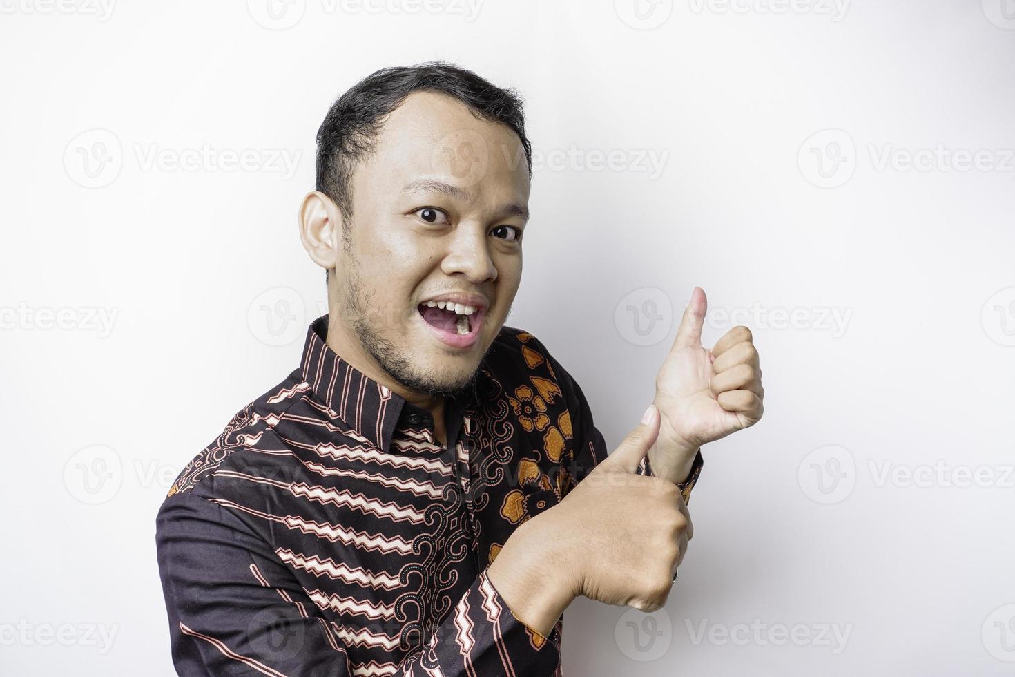 Excited Asian man wearing batik shirt pointing at the copy space on top ...