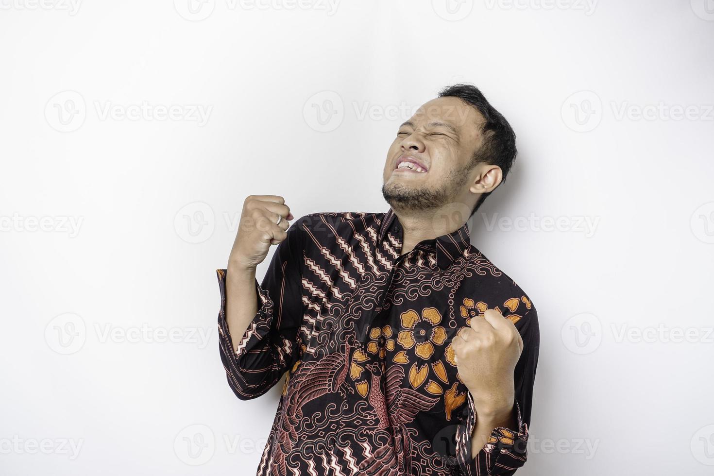 A young Asian man with a happy successful expression wearing batik ...