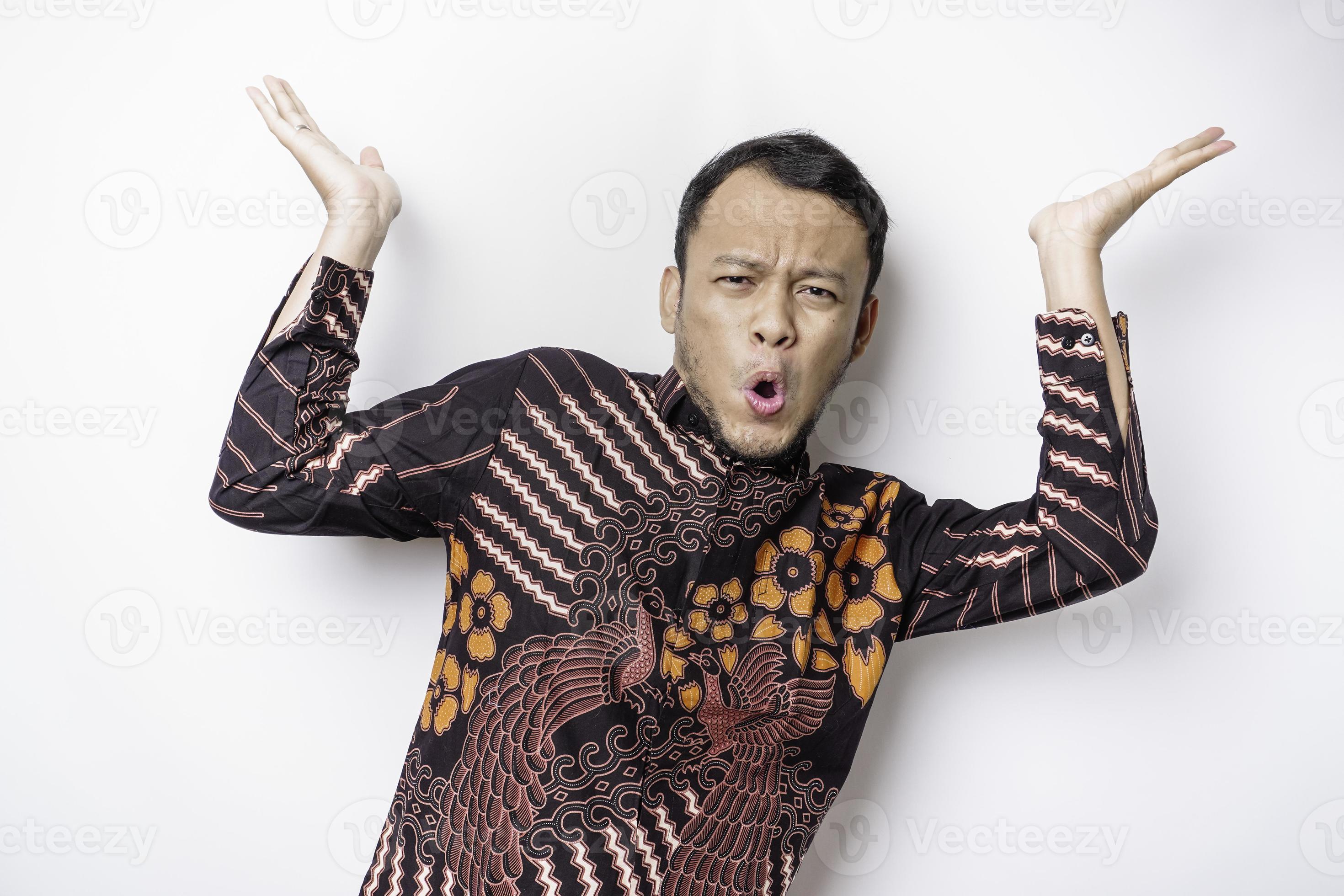 Shocked Asian man wearing batik shirt pointing at the copy space on top ...