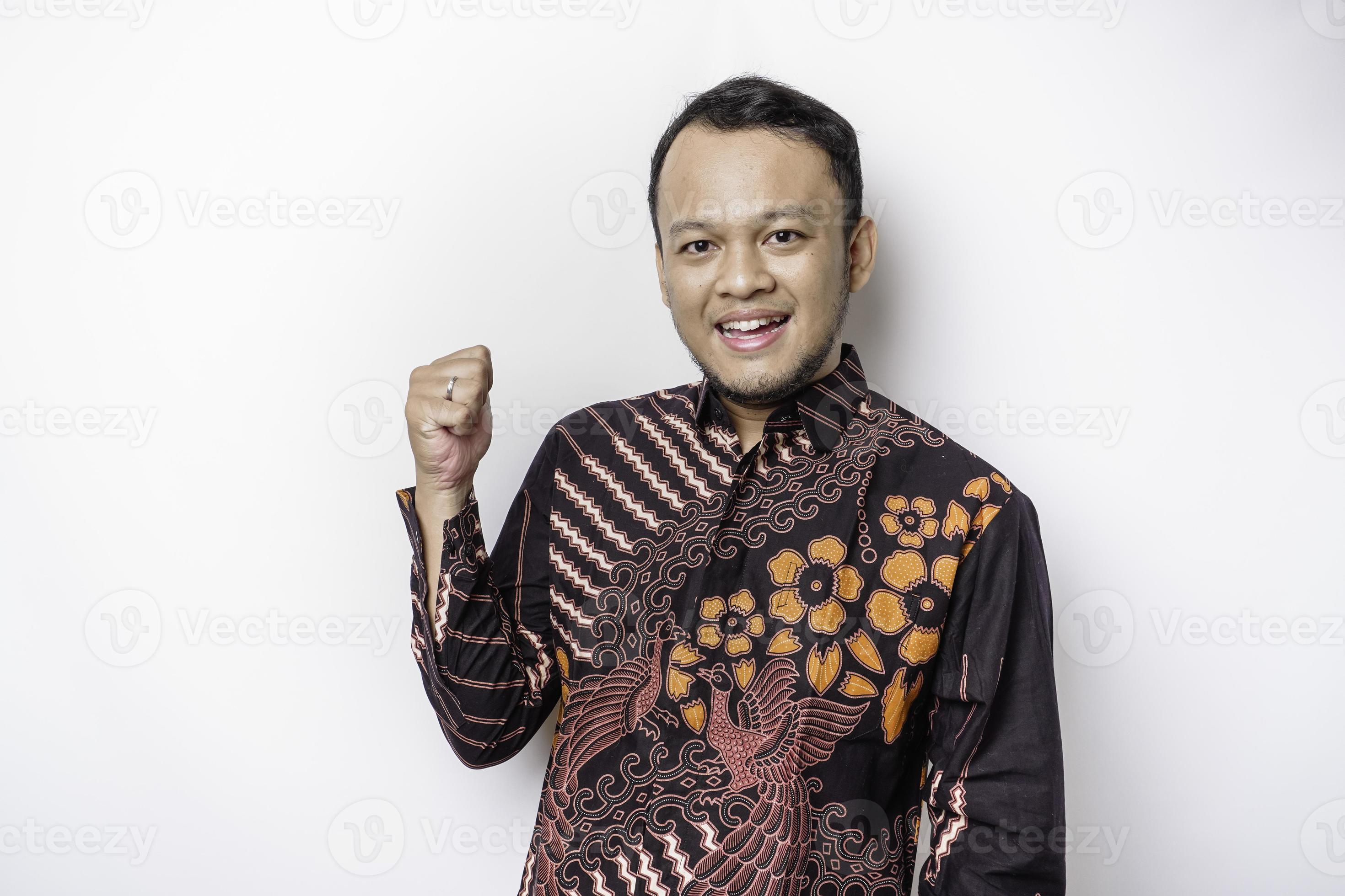 Excited Asian man wearing batik shirt pointing at the copy space beside ...