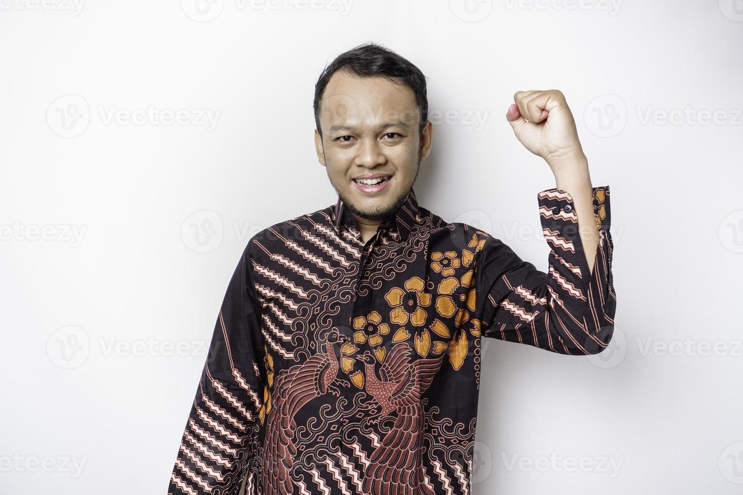 A young Asian man with a happy successful expression wearing batik ...