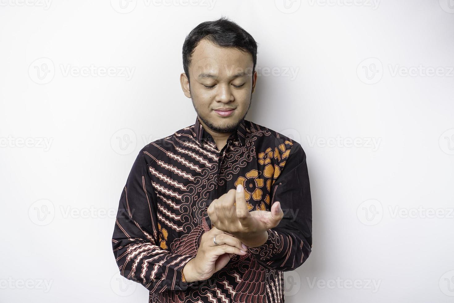 A stylish Asian man wearing batik shirt buttoning up shirt sleeves ...