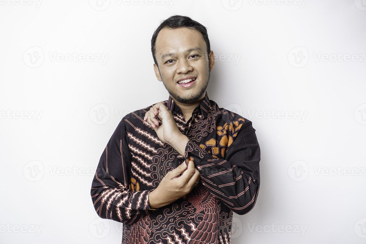 A stylish Asian man wearing batik shirt buttoning up shirt sleeves ...