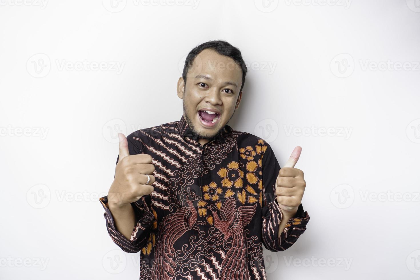 Excited Asian man wears batik shirt, gives thumbs up hand gesture of ...
