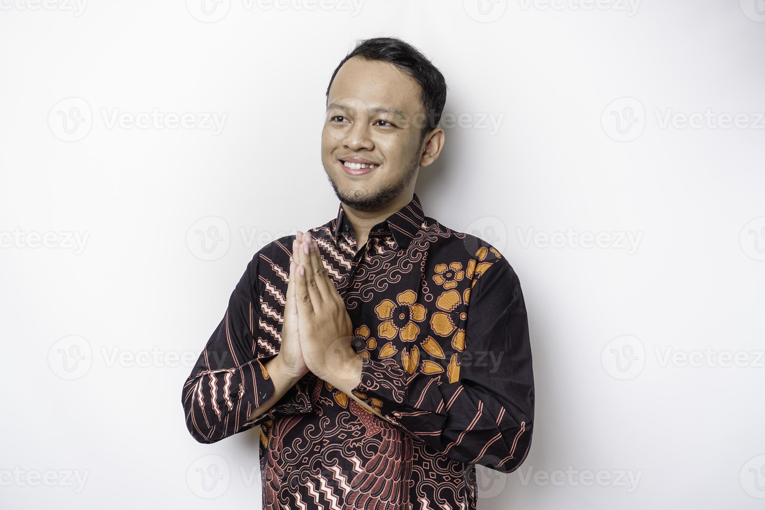 Smiling young Asian man wearing batik shirt, gesturing traditional ...
