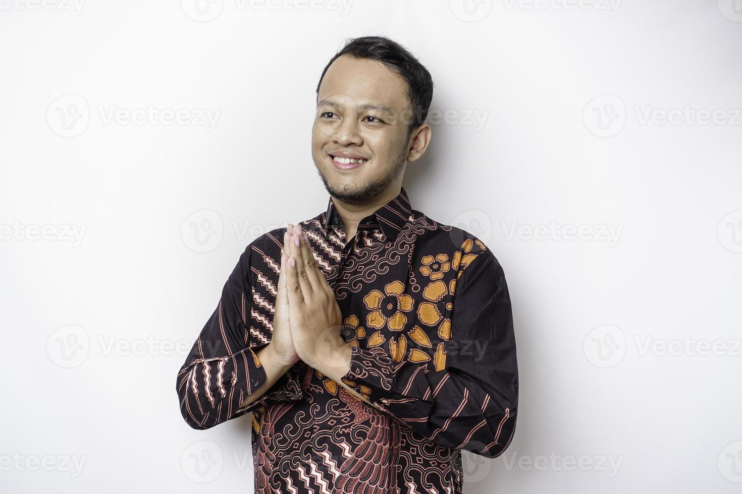 Smiling young Asian man wearing batik shirt, gesturing traditional ...