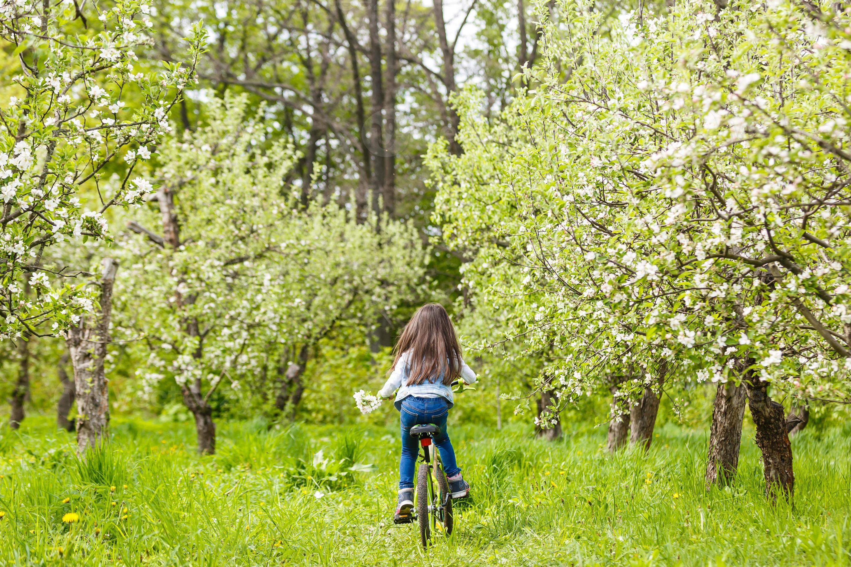 niño andando en bicicleta en la calle con cerezos en flor en los suburbios. niño en bicicleta al ...