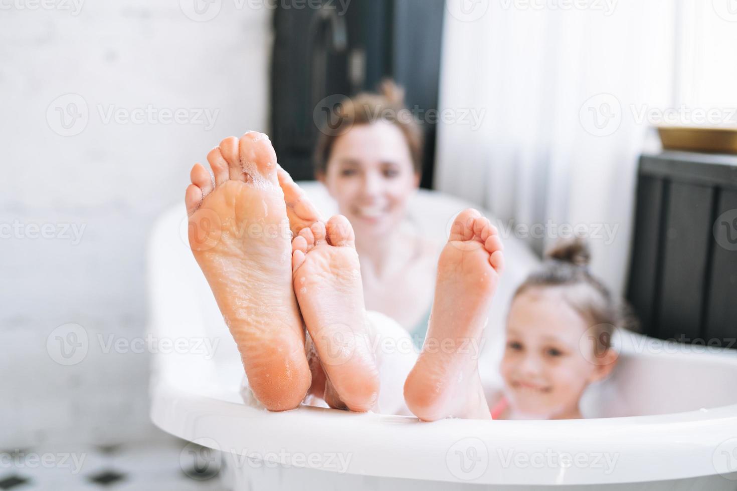 Young mother woman and little tween girl daughter having fun in bath with foam at home 16663012 ...