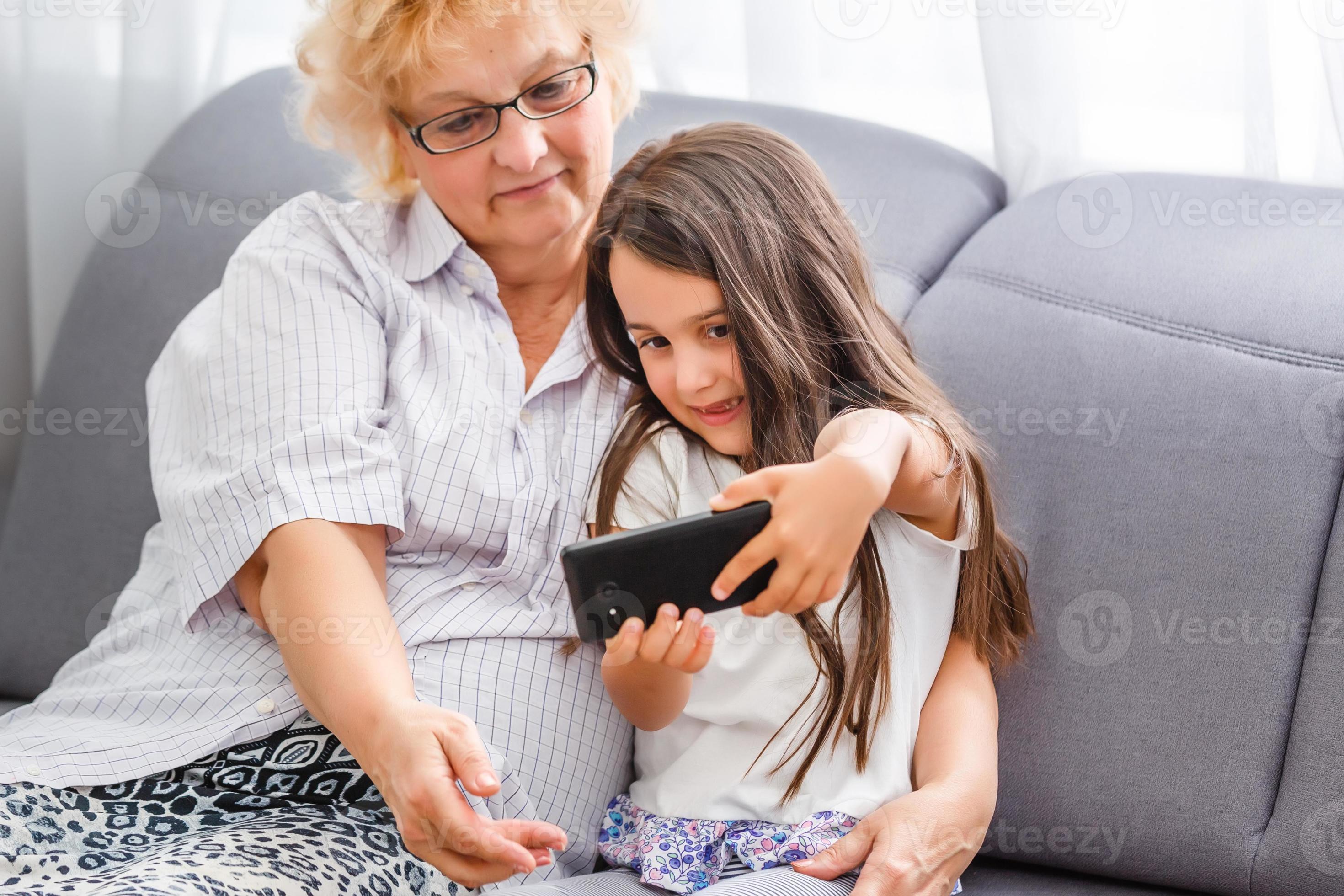 Happy Grandmother And Cute Granddaughter Using Cellphone Together