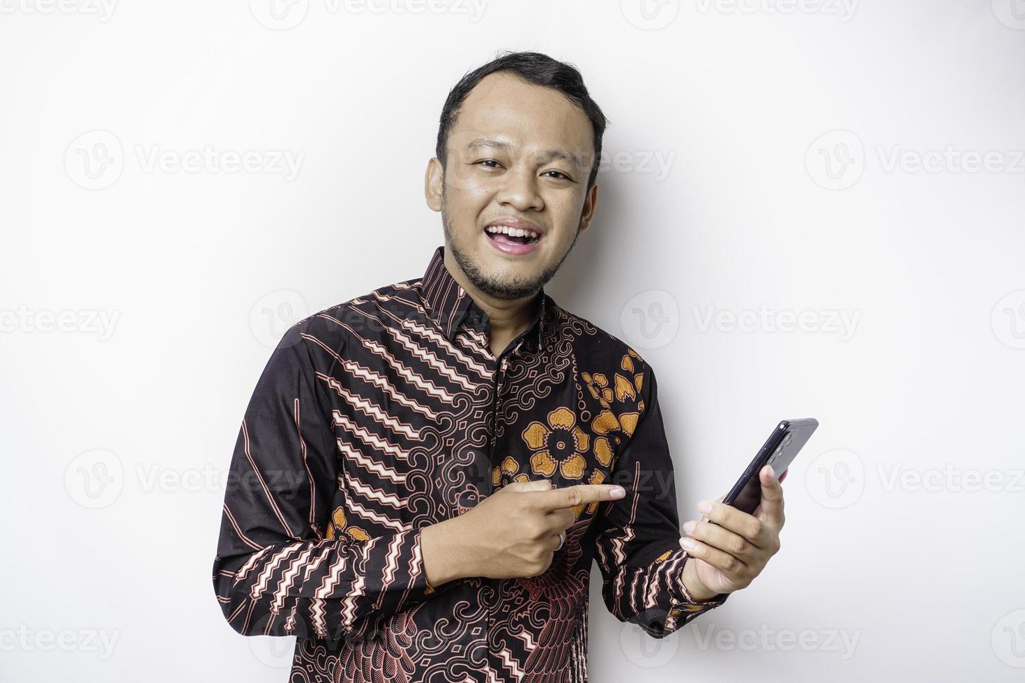 A portrait of a happy Asian man wearing batik shirt and holding his ...