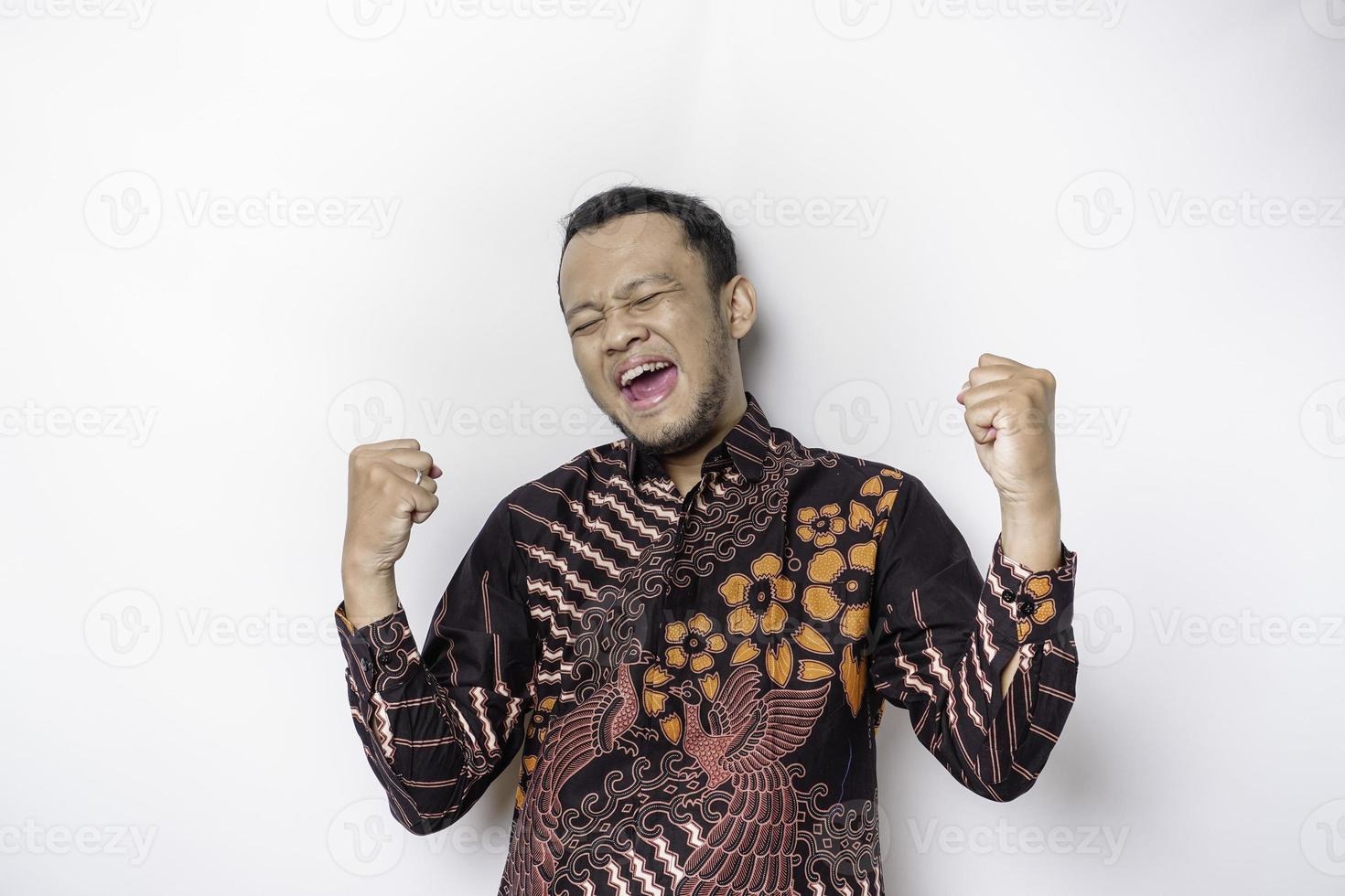 A young Asian man with a happy successful expression wearing batik ...