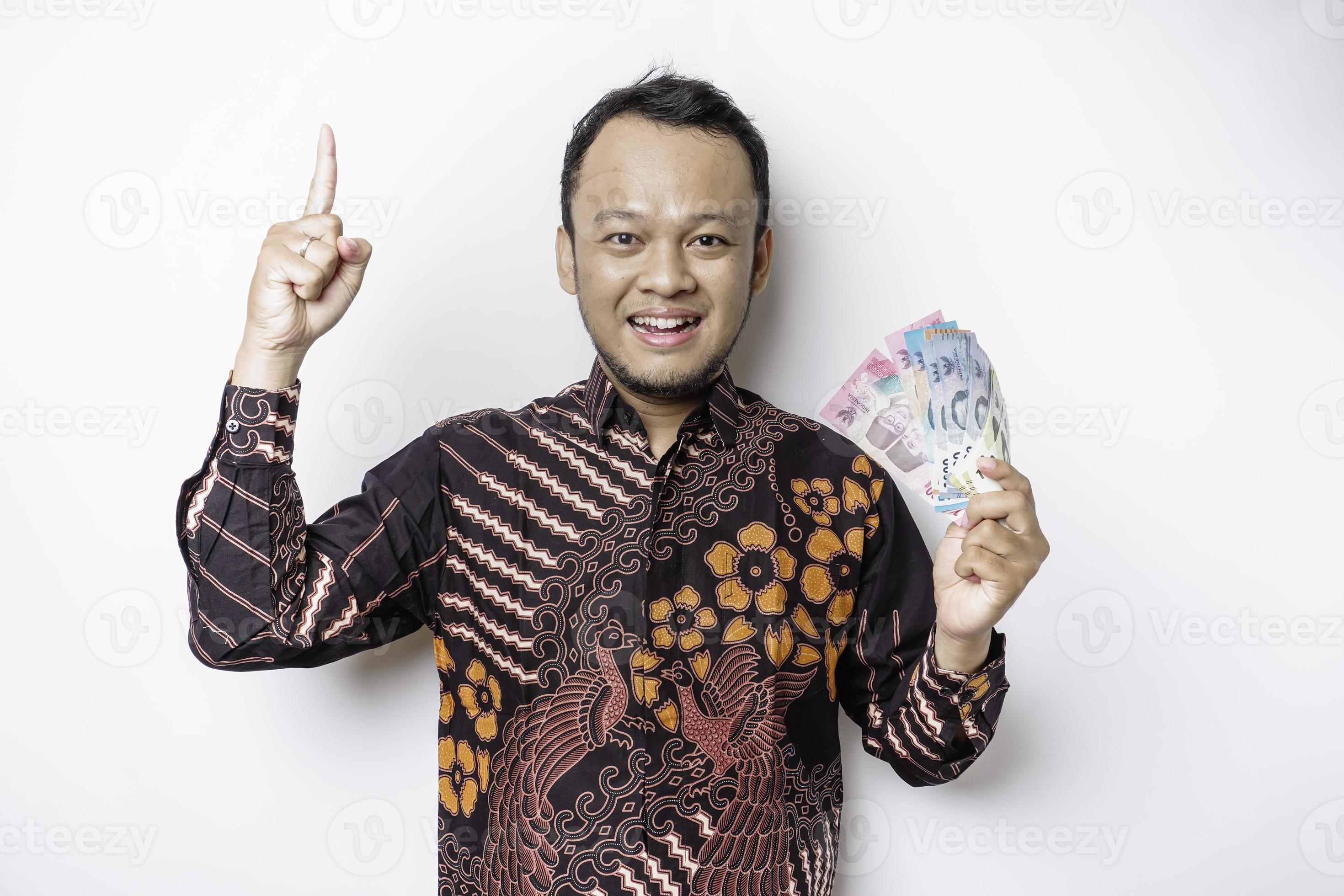 A happy young Asian man is wearing batik shirt, pointing at the copy ...