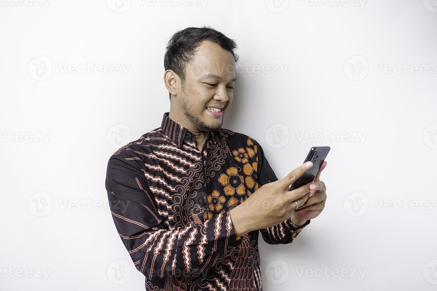 A portrait of a happy Asian man wearing batik shirt and holding his ...