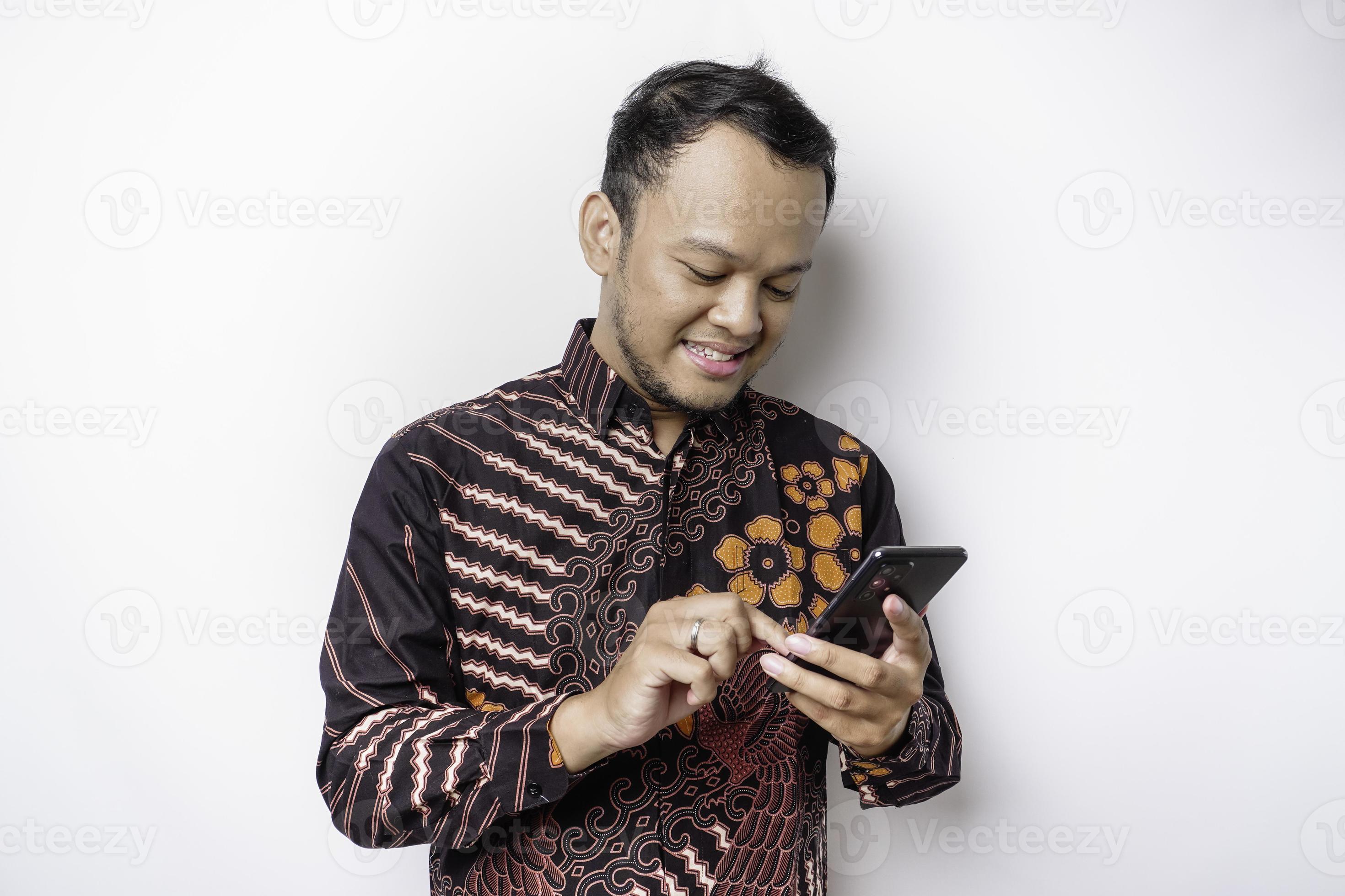 A portrait of a happy Asian man wearing batik shirt and holding his ...