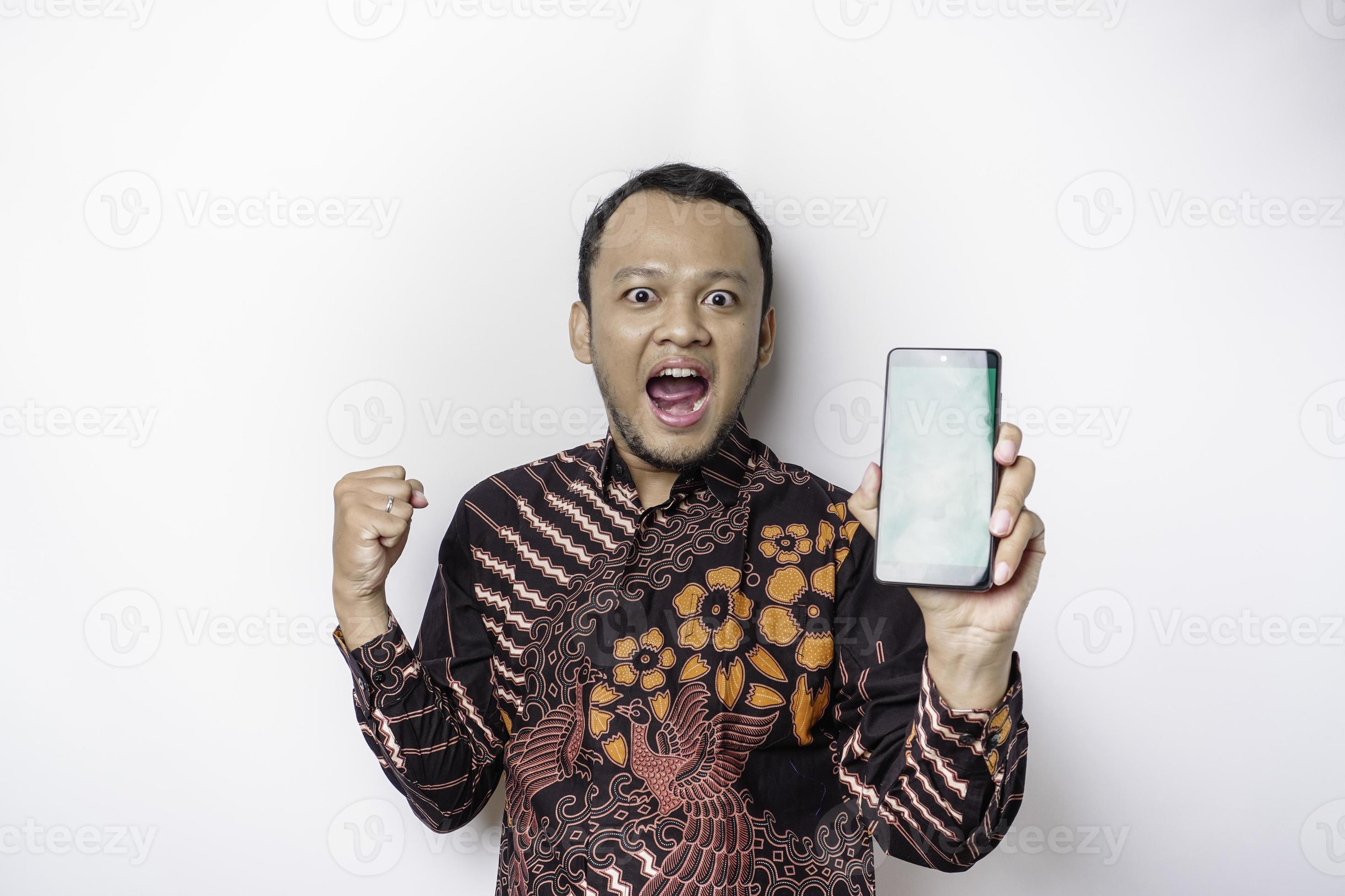 A happy young Asian man wearing batik shirt showing successful ...