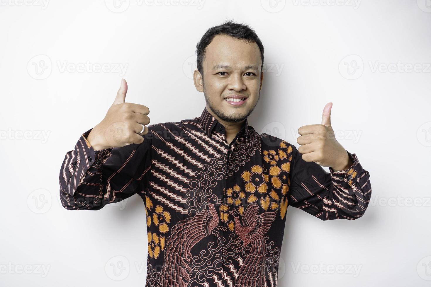 Excited Asian man wears batik shirt, gives thumbs up hand gesture of ...