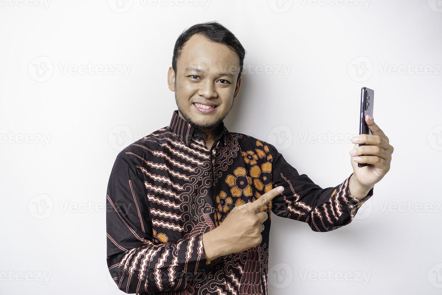 A portrait of a happy Asian man wearing batik shirt and holding his ...