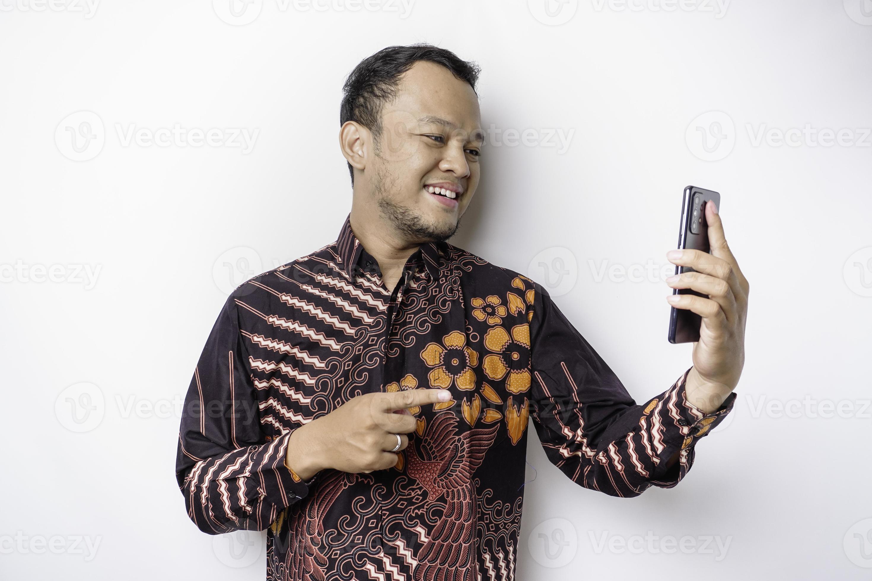 A portrait of a smiling Asian man wearing a batik shirt and showing ...