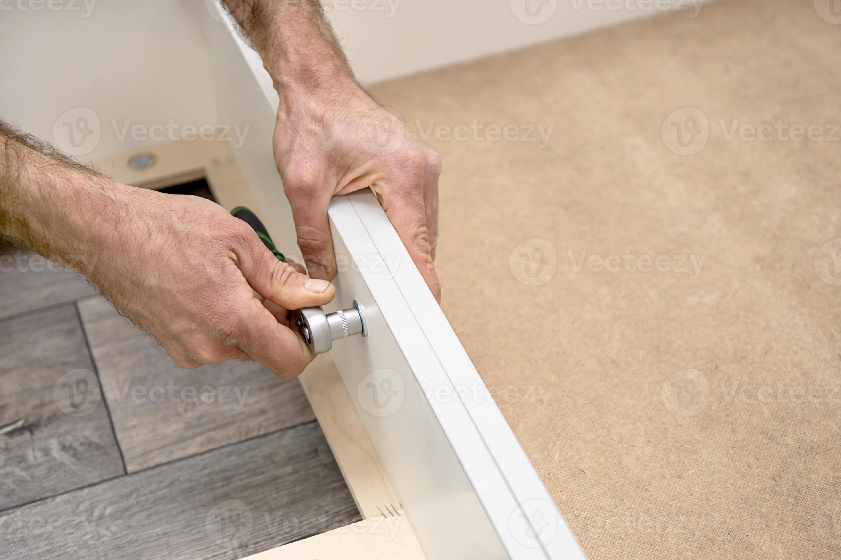 Workers Assembling Furniture At Home Hands Tightening The Bolt