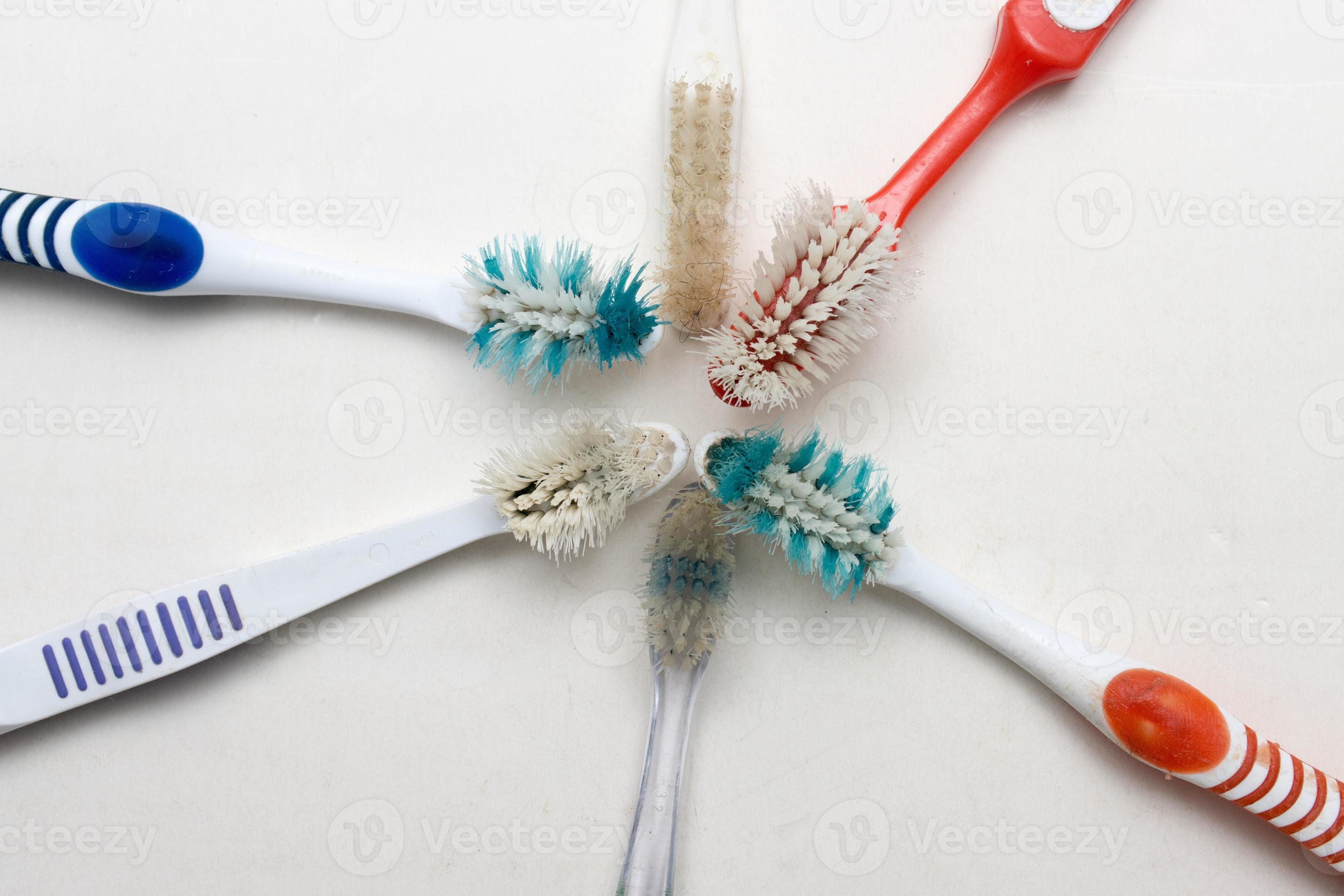 A bunch of old worn out toothbrushes with bent bristles on a white ...