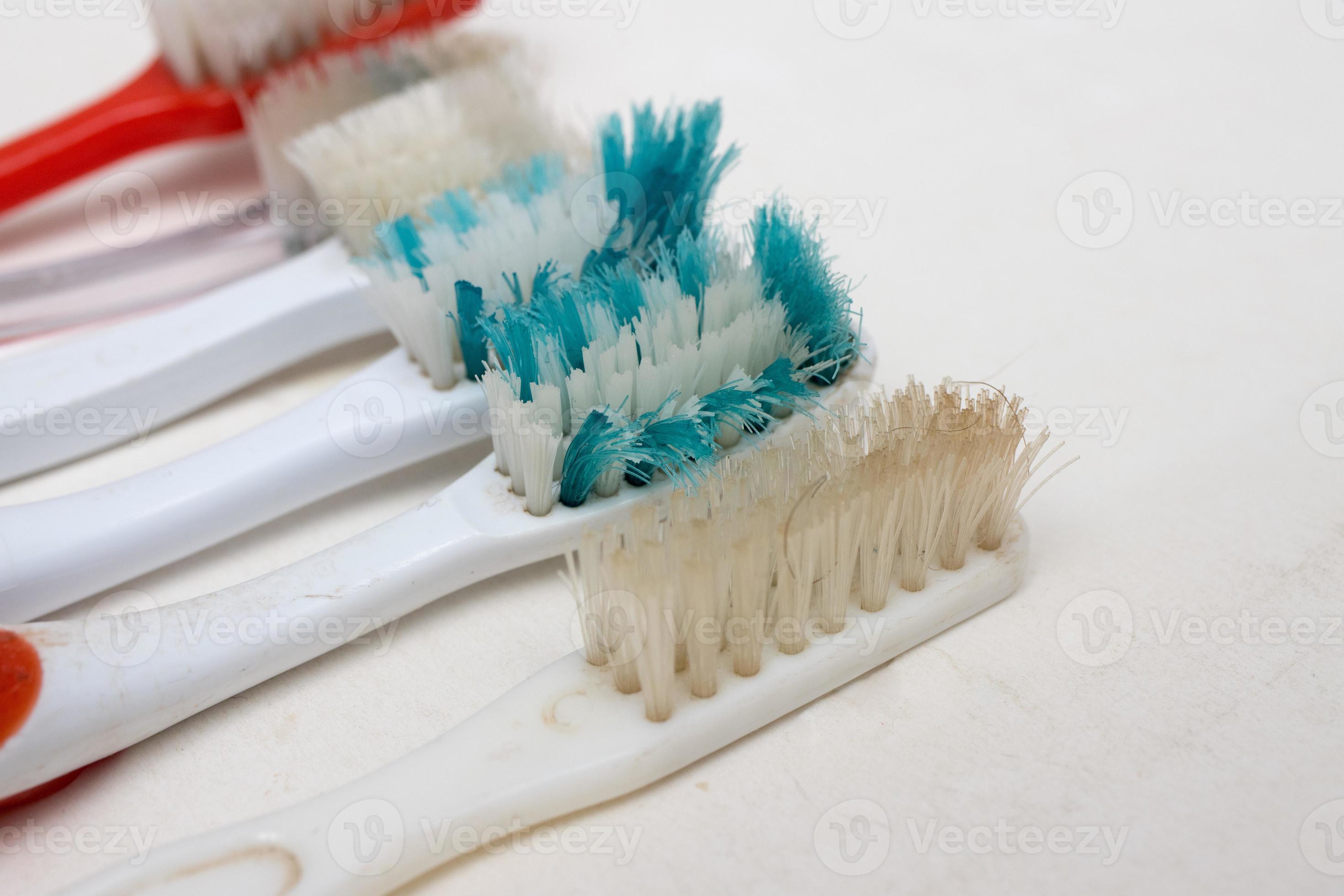 A bunch of old worn out toothbrushes with bent bristles on a white ...