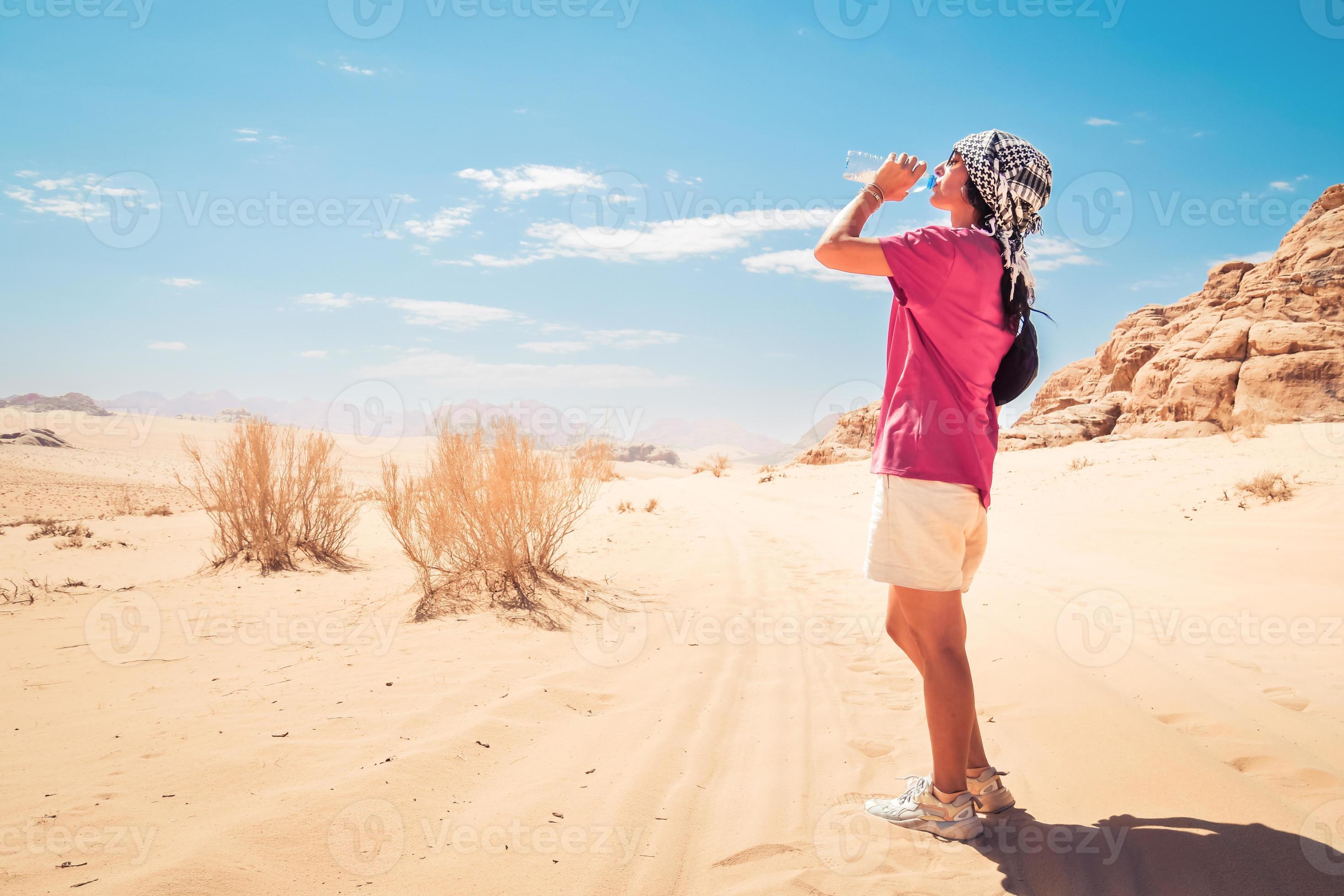 Caucasian woman thirsty drink cold fresh water in extreme heat in hot wadi rum desert outdoors ...