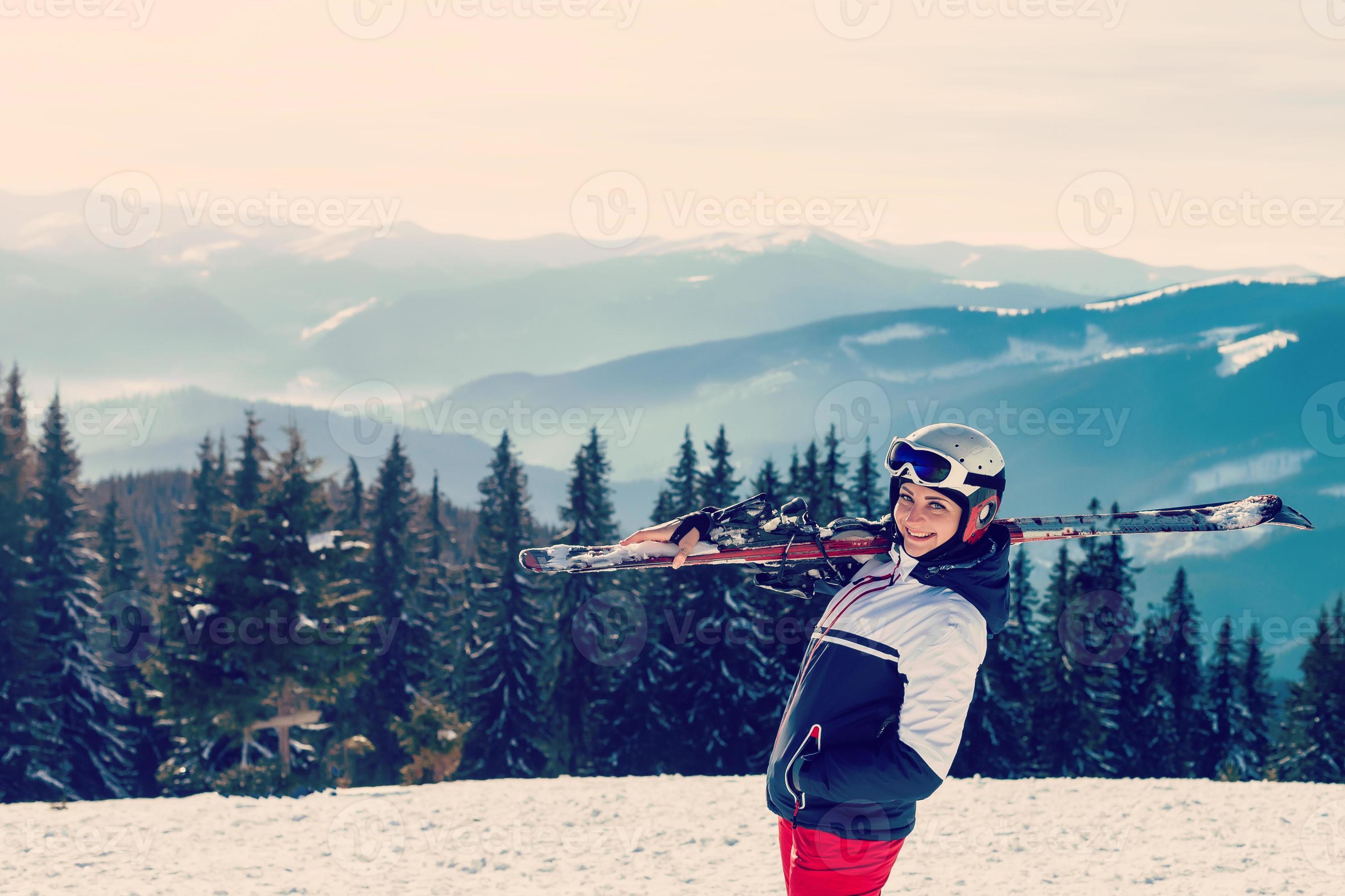 Female skier standing on top of a hill enjoying beautiful scenery on ...