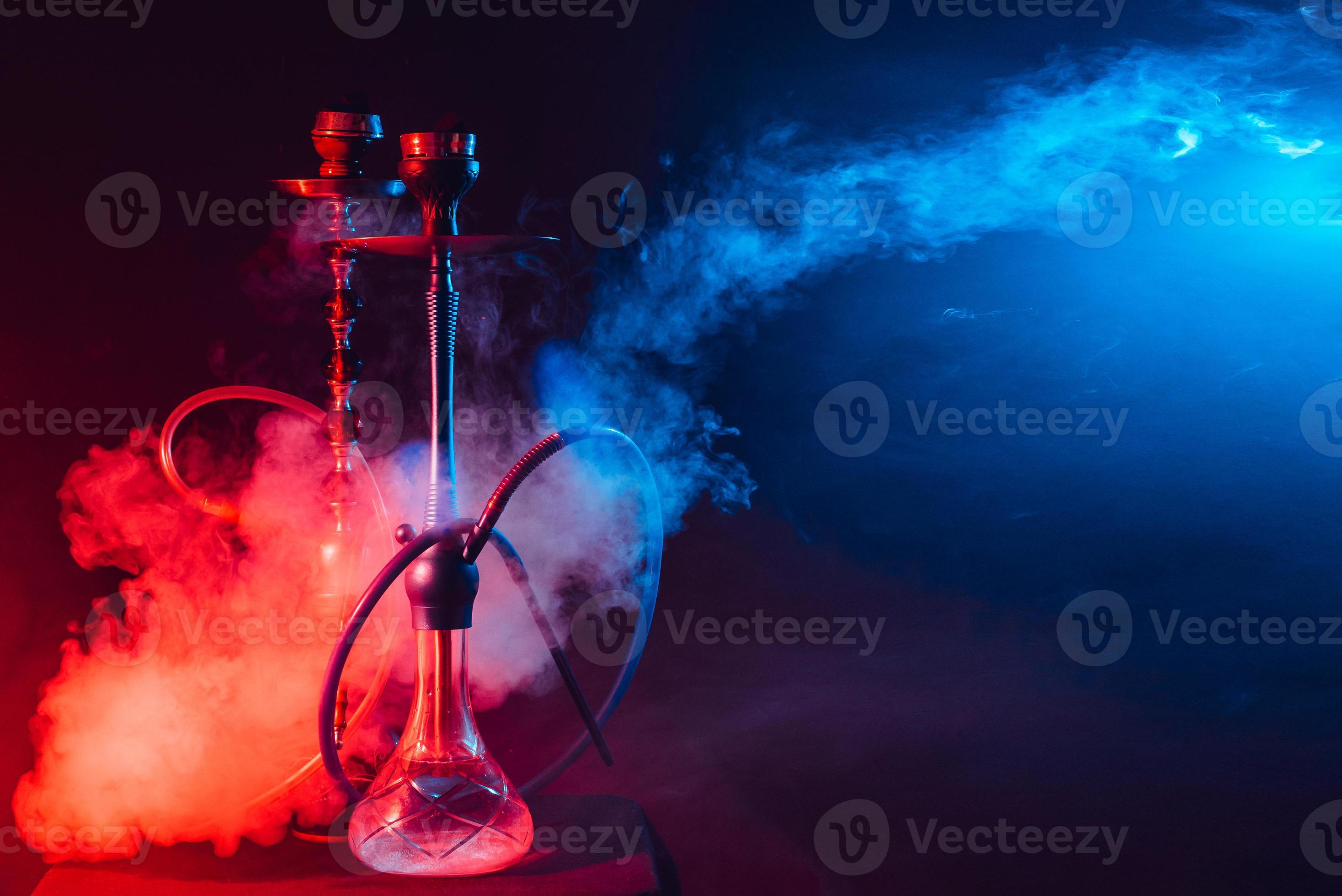 Modern hookah, shisha on a smoky black background with neon lighting and smoke. Place for your ...