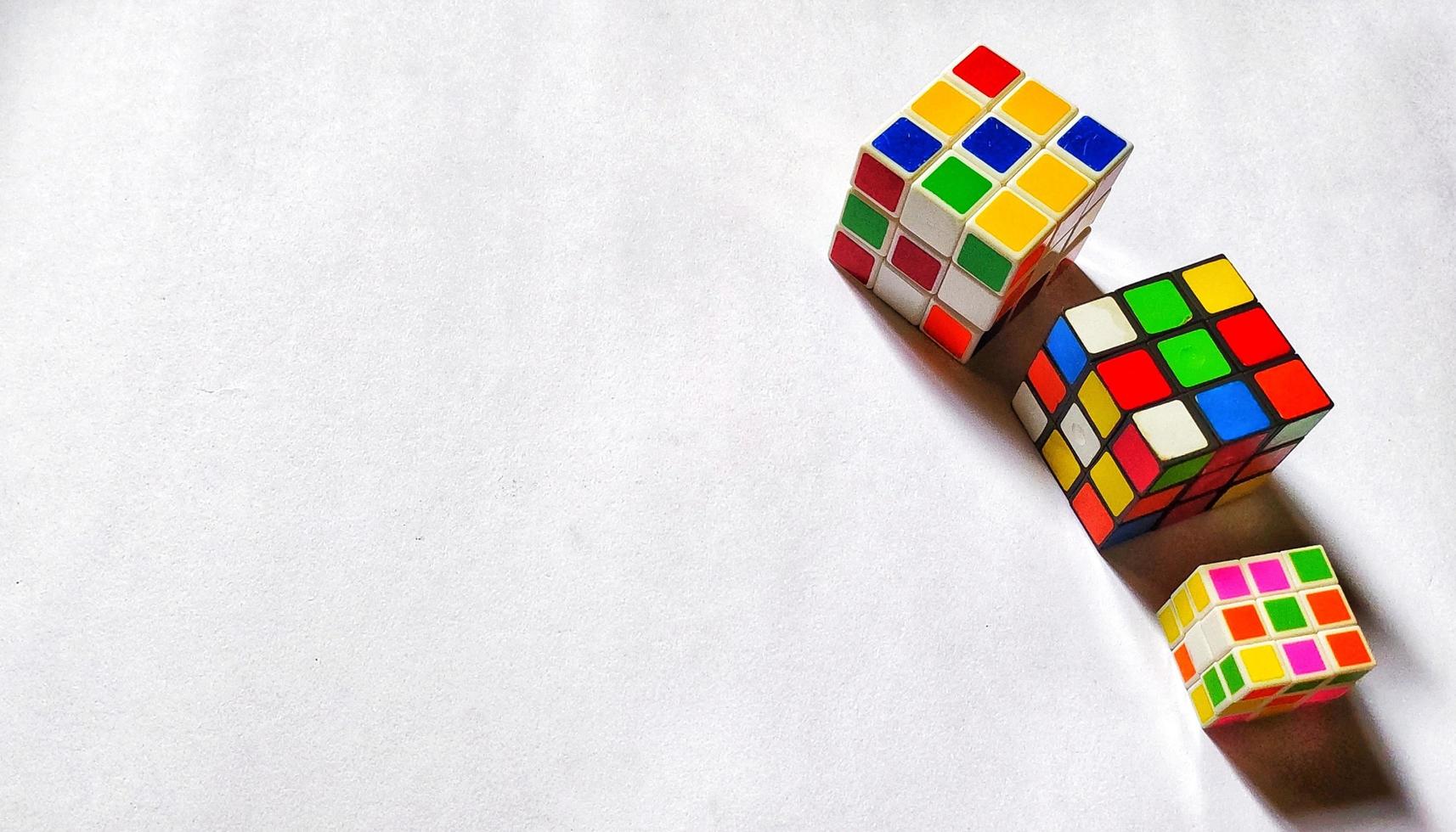 Jakarta, December 2022. Three rubik's cubes of different sizes and colors isolated on white ...
