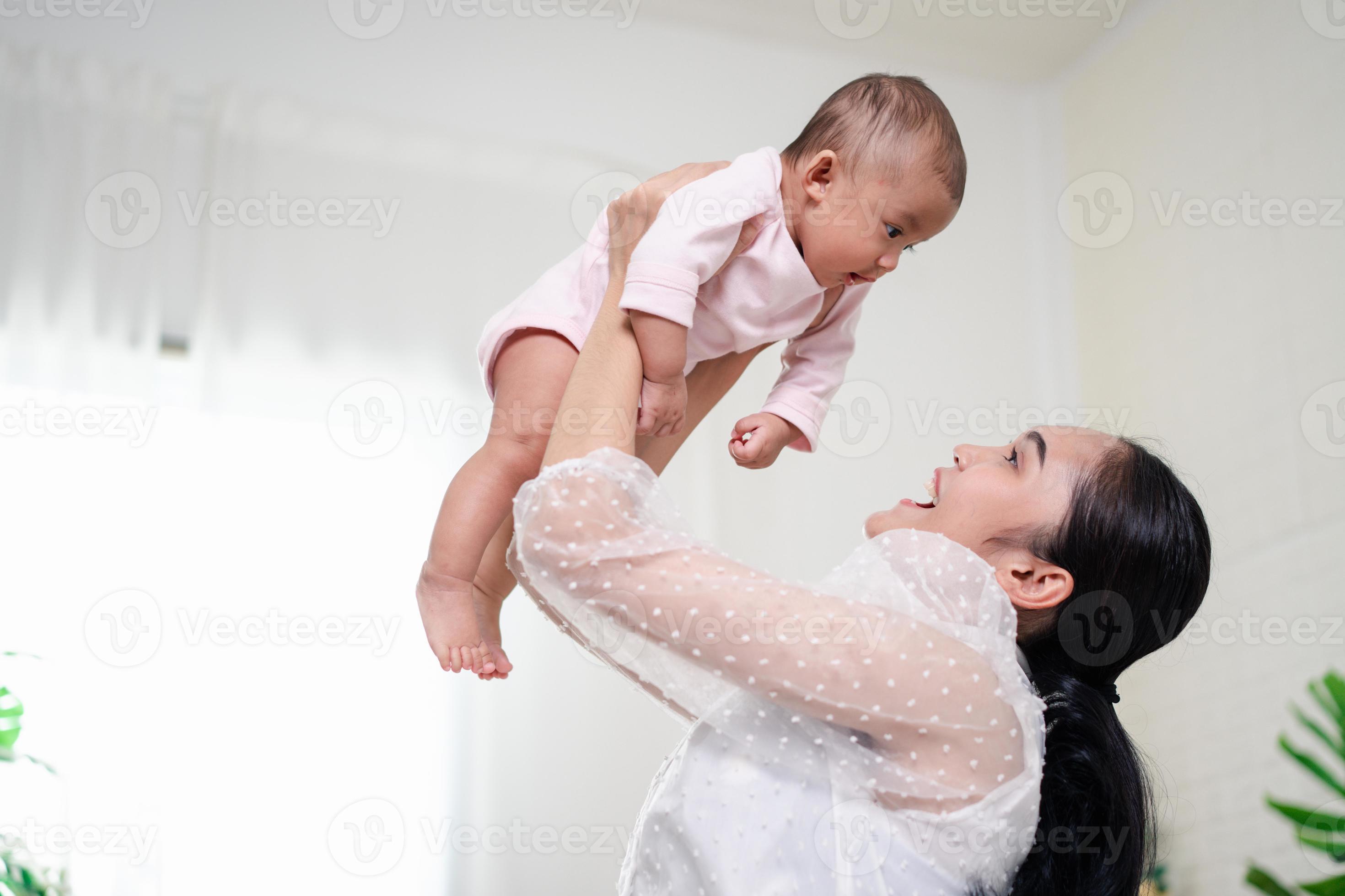 Mother Parenting and newborn birth life. Mom and baby boy playing in sunny bedroom, Family ...
