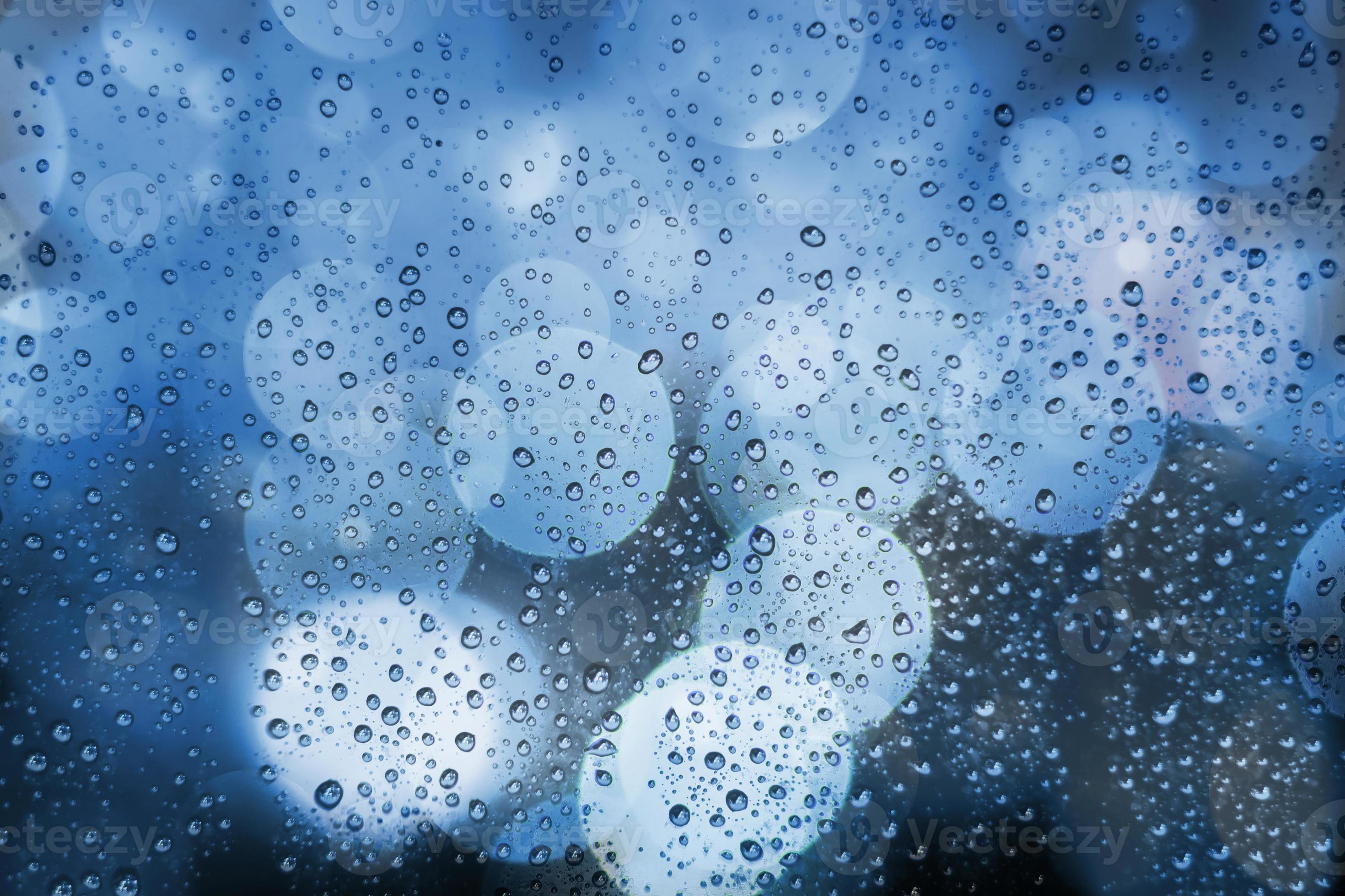 Abstract background with raindrops and soft blue bokeh. Defocused lights and water droplets on ...