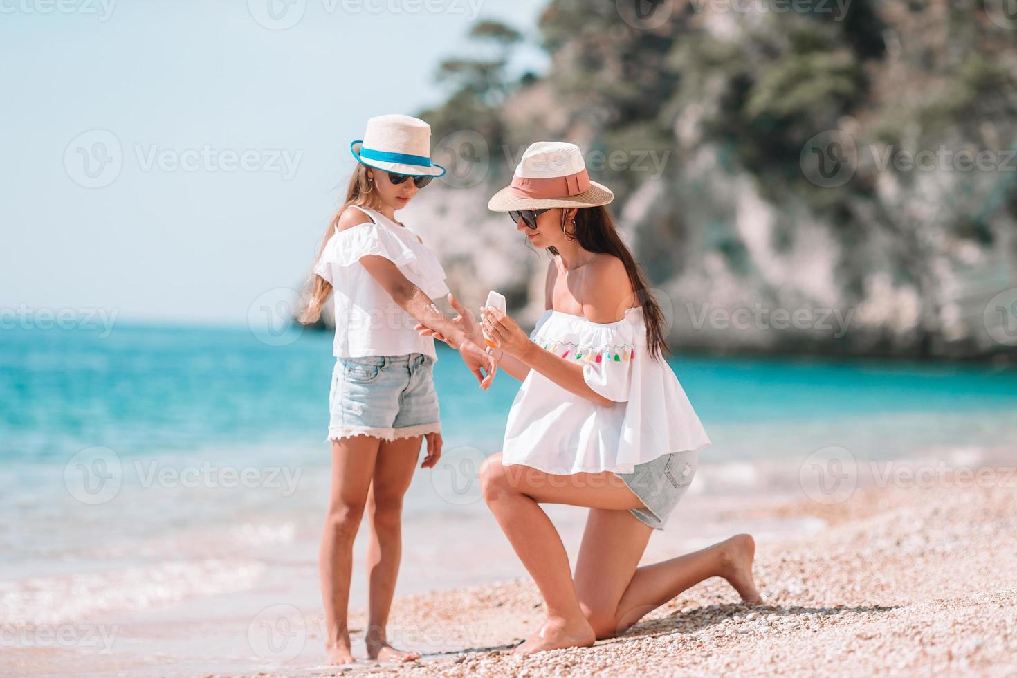 Mother Applying Sun Protection Cream To Her Daughter At Tropical Beach