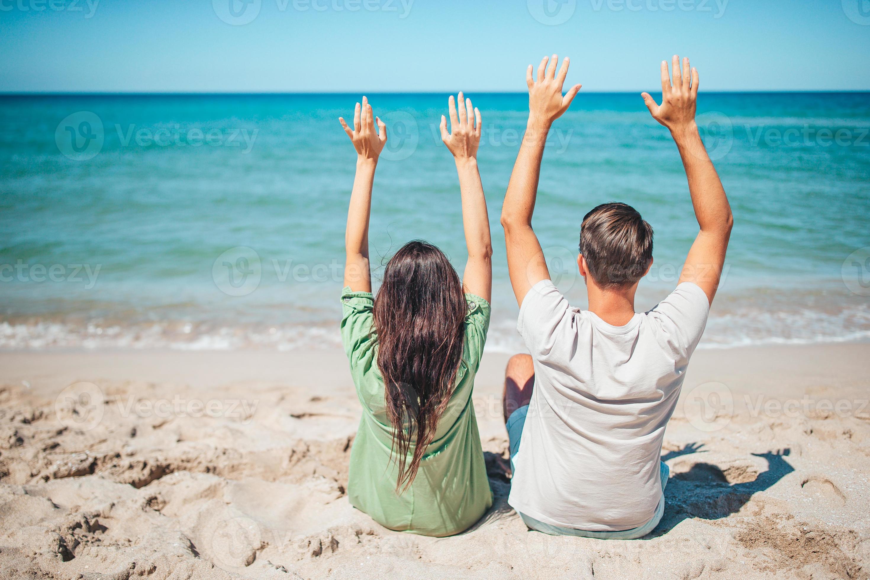 pareja joven en las vacaciones de verano en la playa. hombre y mujer felices miran el mar ...