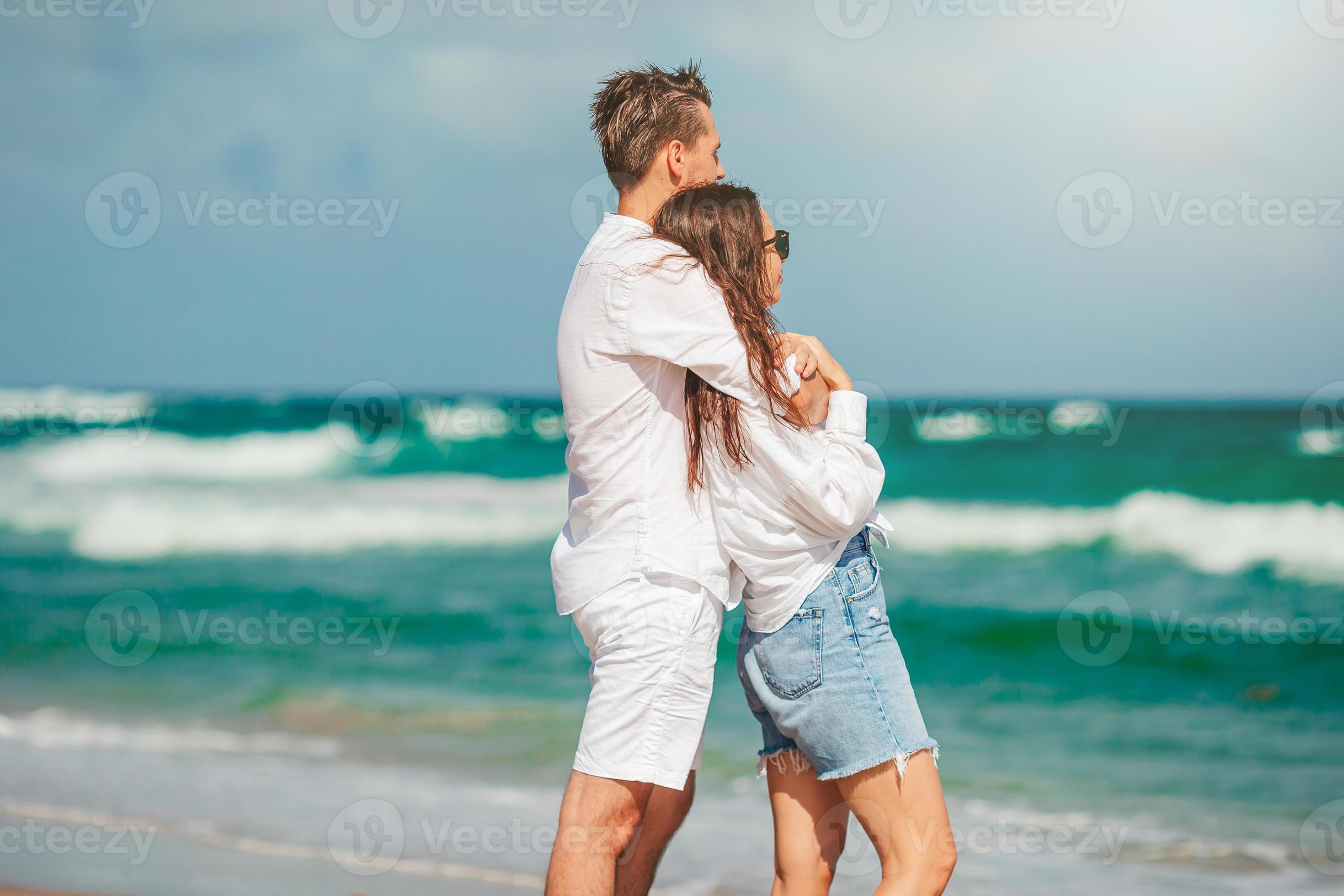 joven pareja de enamorados en las vacaciones de verano en la playa. hombre y mujer felices miran ...