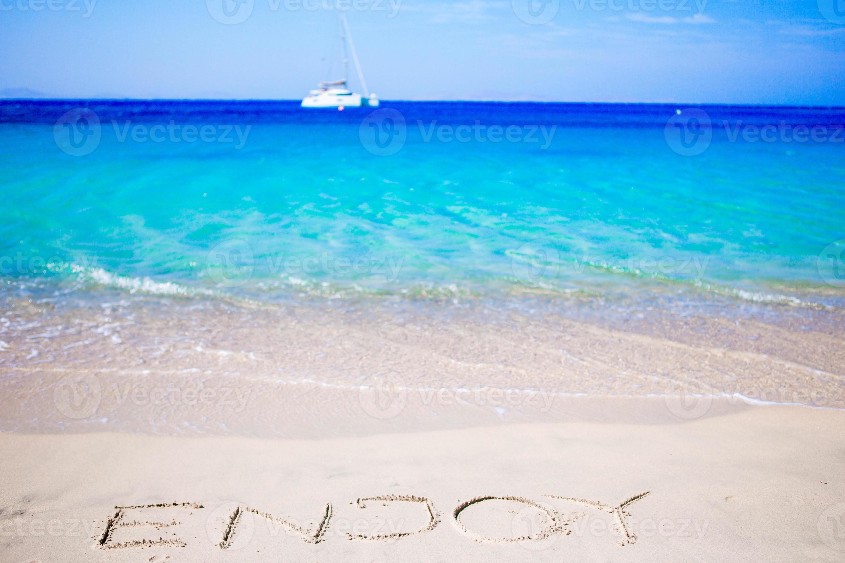 Word Enjoy Handwritten On Sandy Beach With Soft Ocean Wave On word-enjoy-handwritten-on-sandy-beach-with-soft-ocean-wave-on