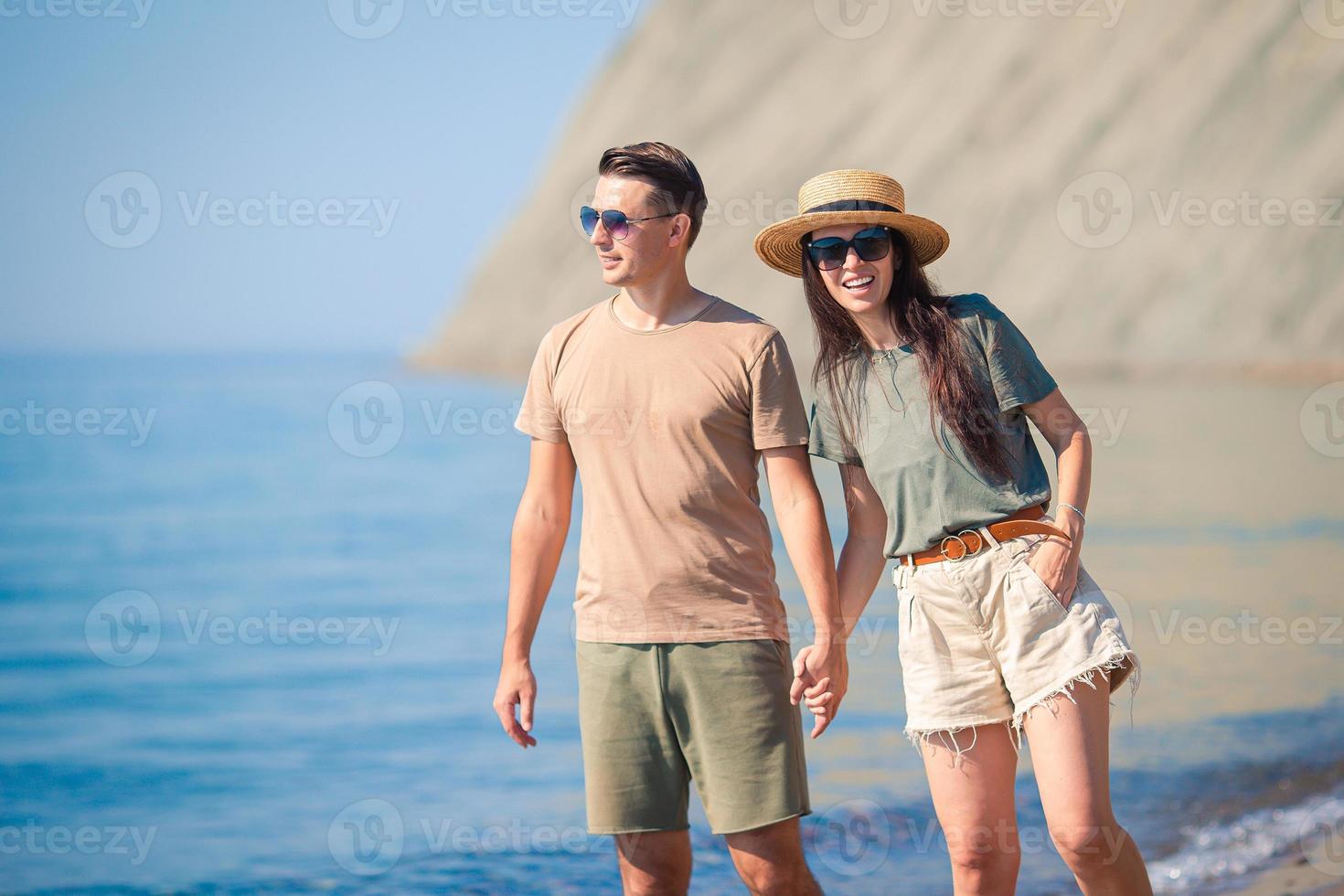 joven pareja de enamorados en las vacaciones de verano en la playa. hombre y mujer felices miran ...