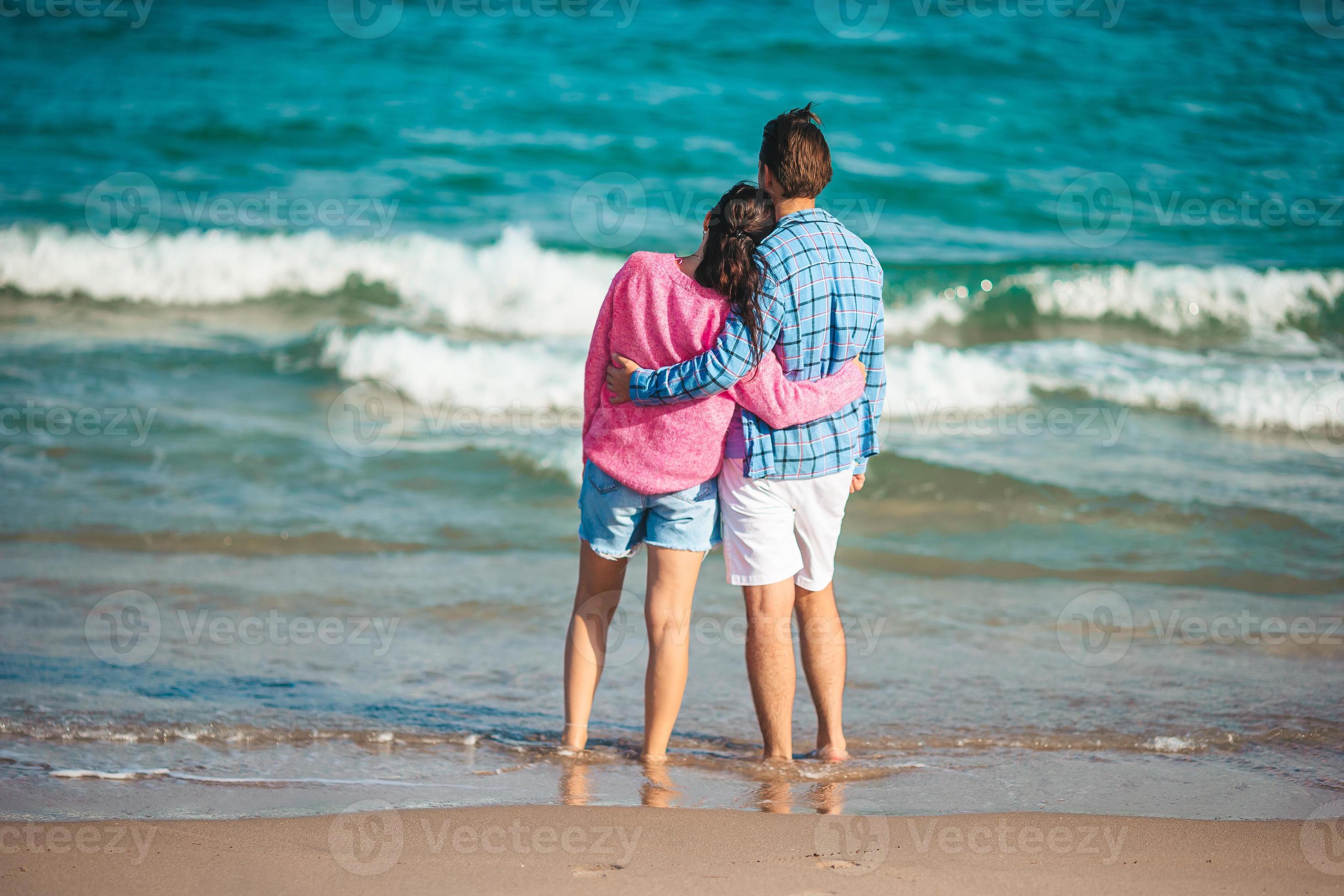 joven pareja de enamorados en las vacaciones de verano en la playa. hombre y mujer felices miran ...