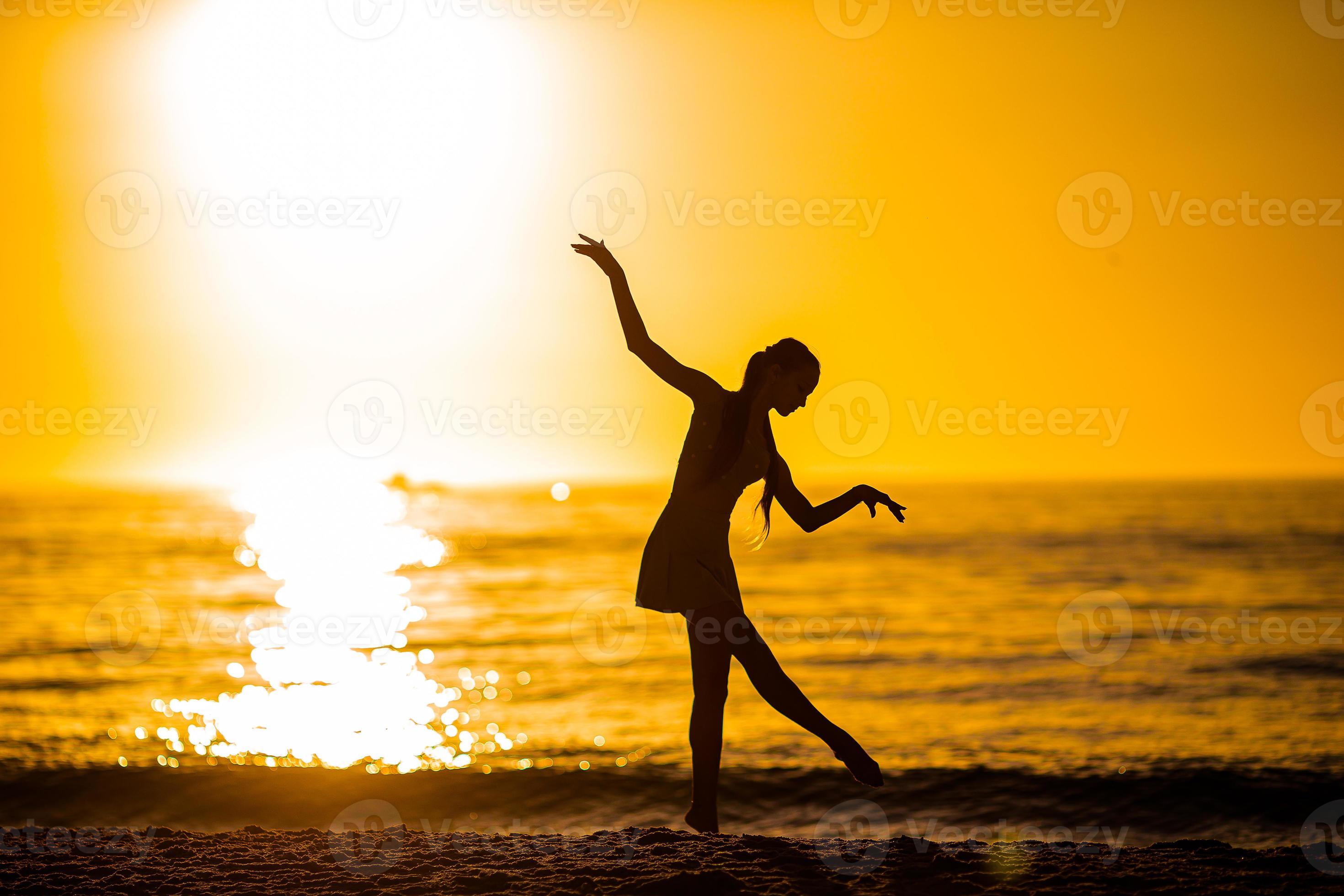 Silhouette Of The Beautiful Girl Dancing On The Beach At Sunset